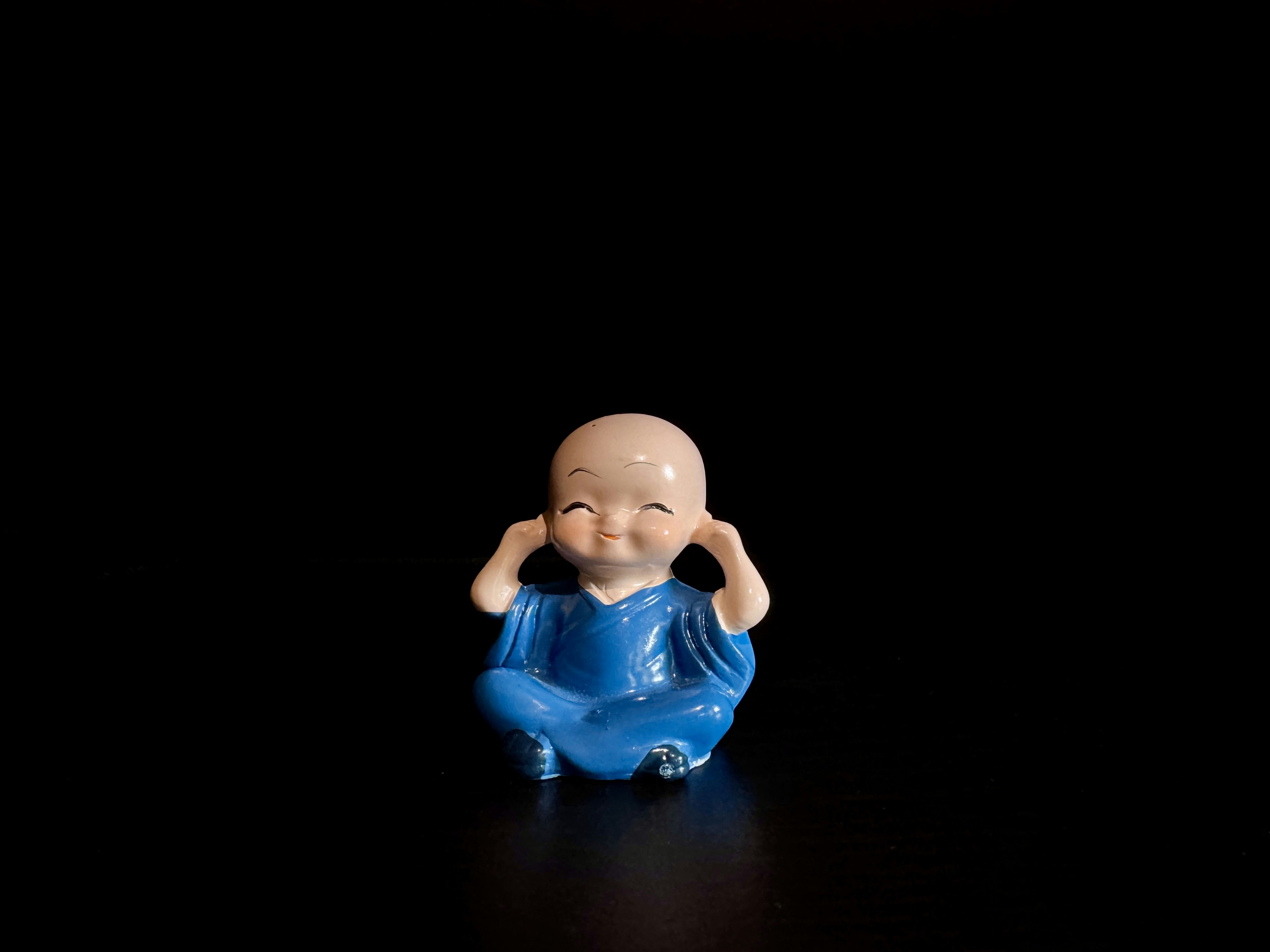 A small monk figurine is blocking his ears.