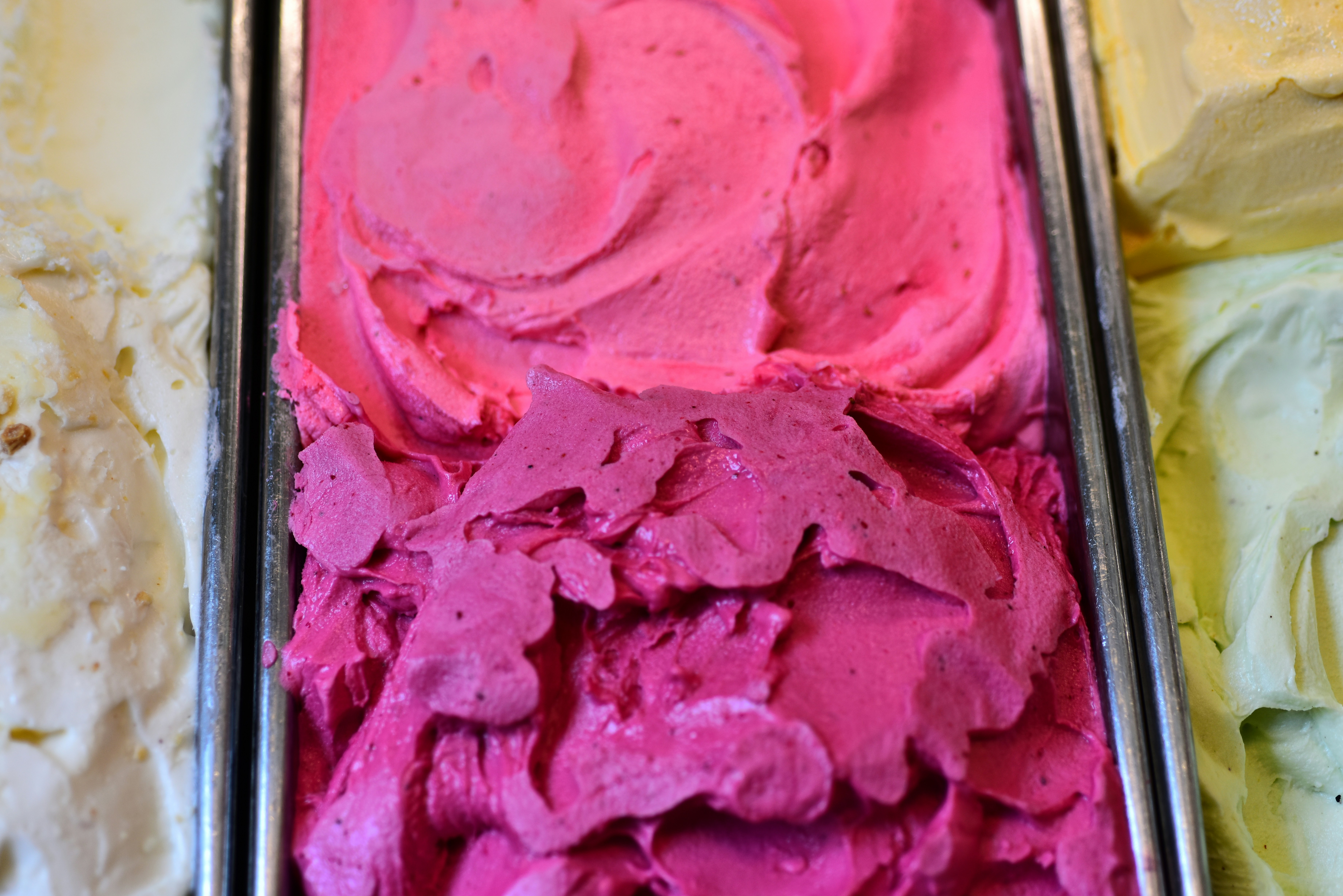Taste the Rainbow: Ice Cream Displayed in Stainless Steel Trays. Frozen Temptations: A View into the Ice Cream Showcase.