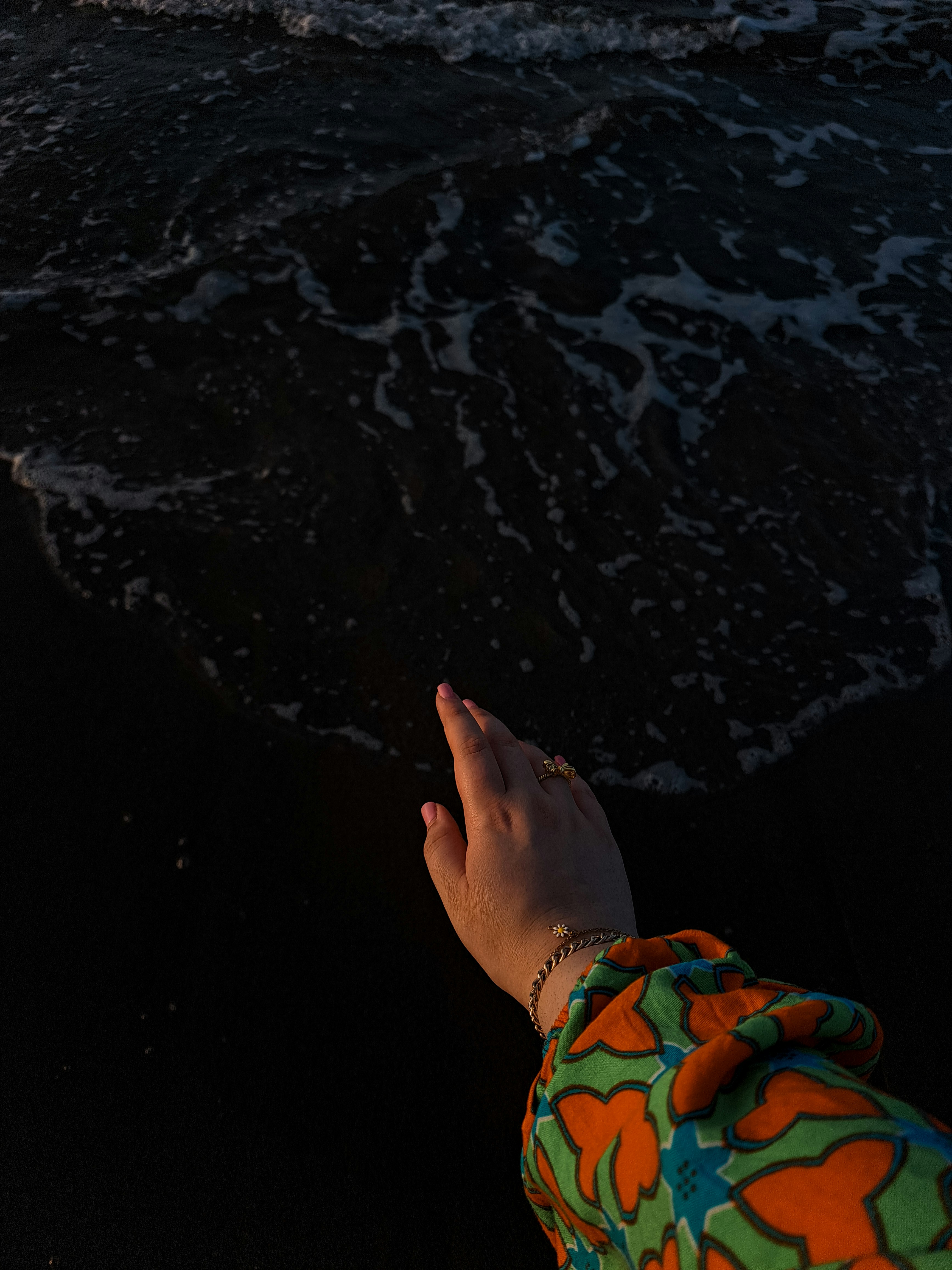 🫳🌊 | Hand and arm reaching toward dark ocean waves.