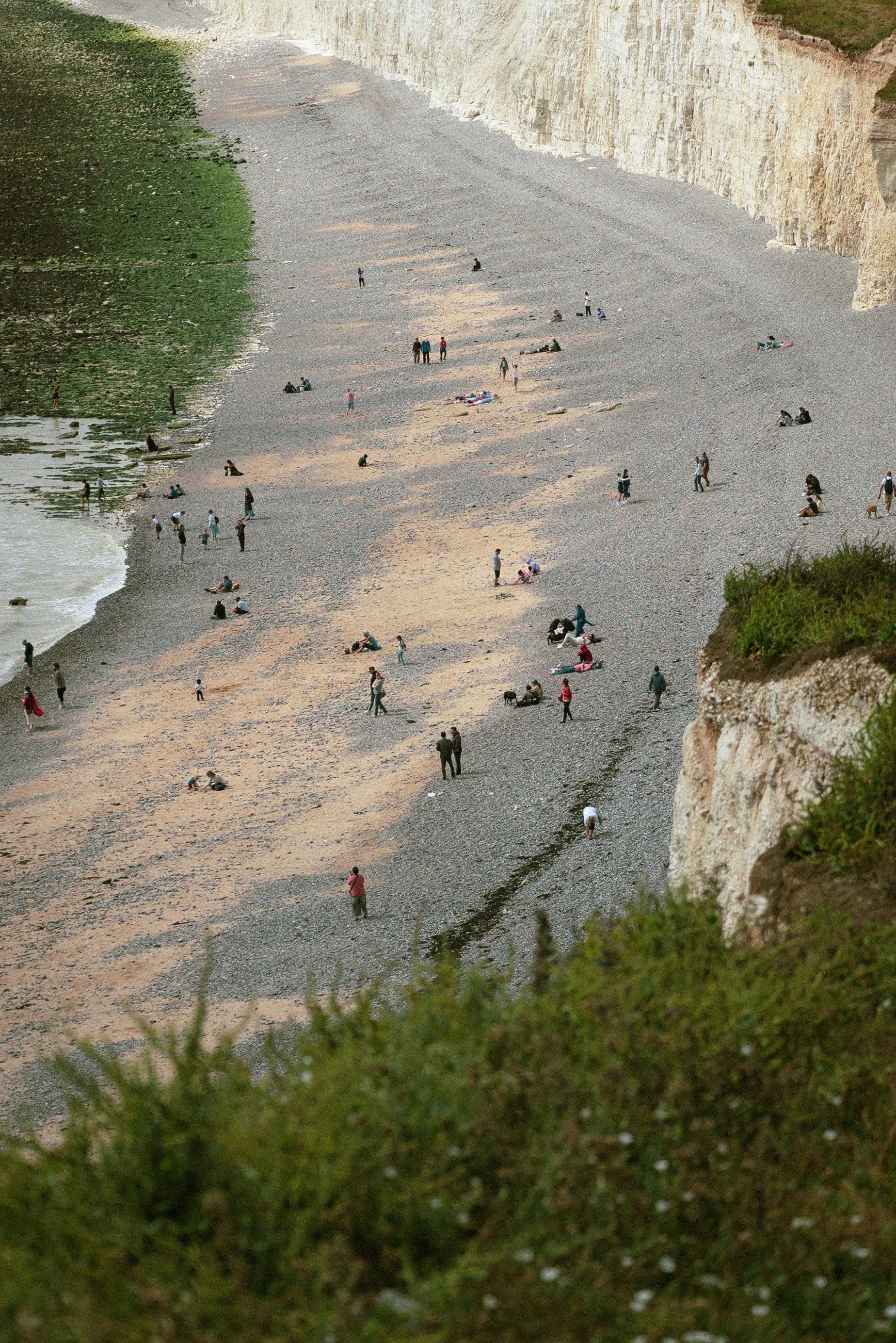 People relax on a beach between cliffs.