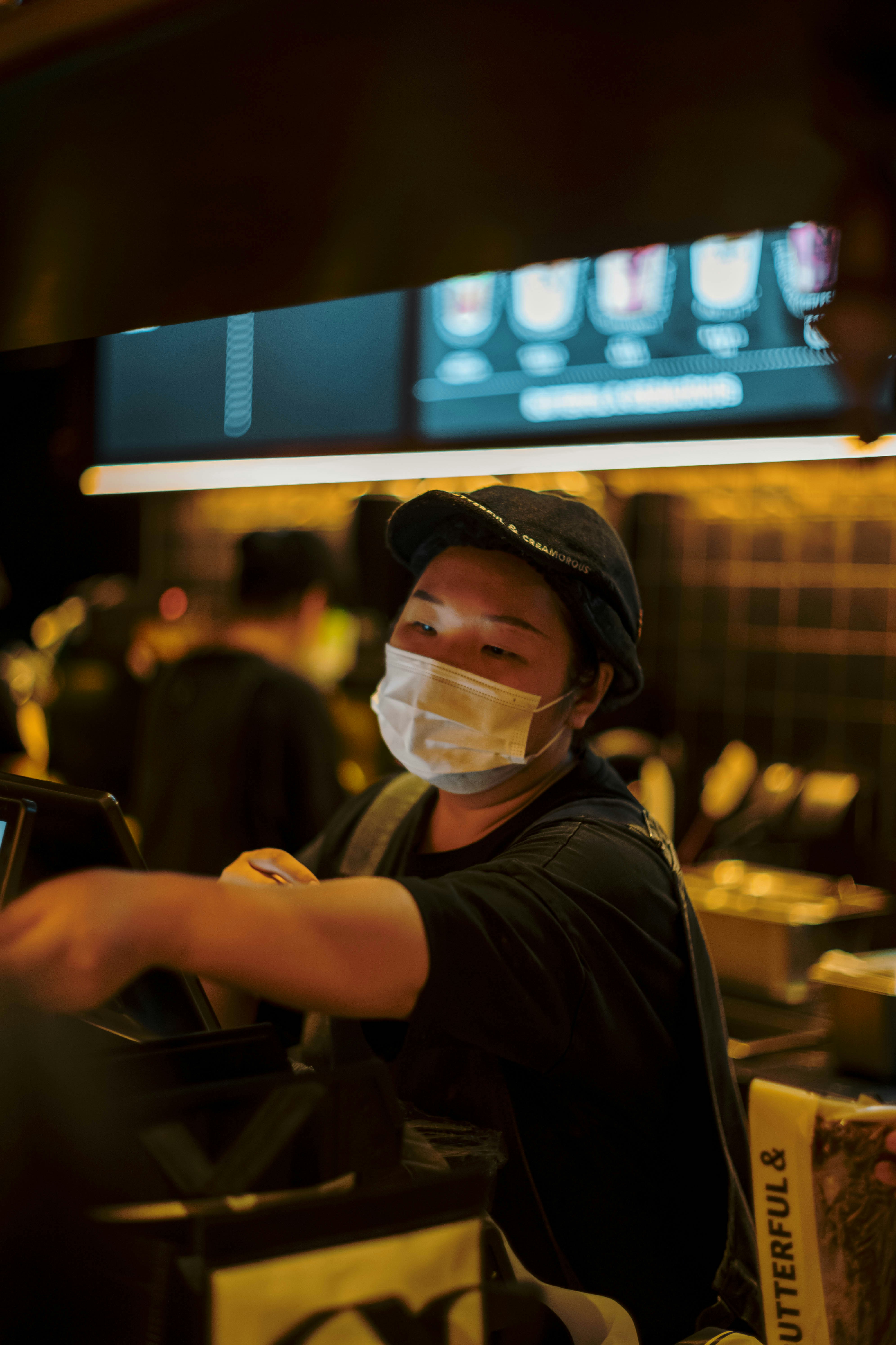 A barista is working in a cafe while wearing a mask.