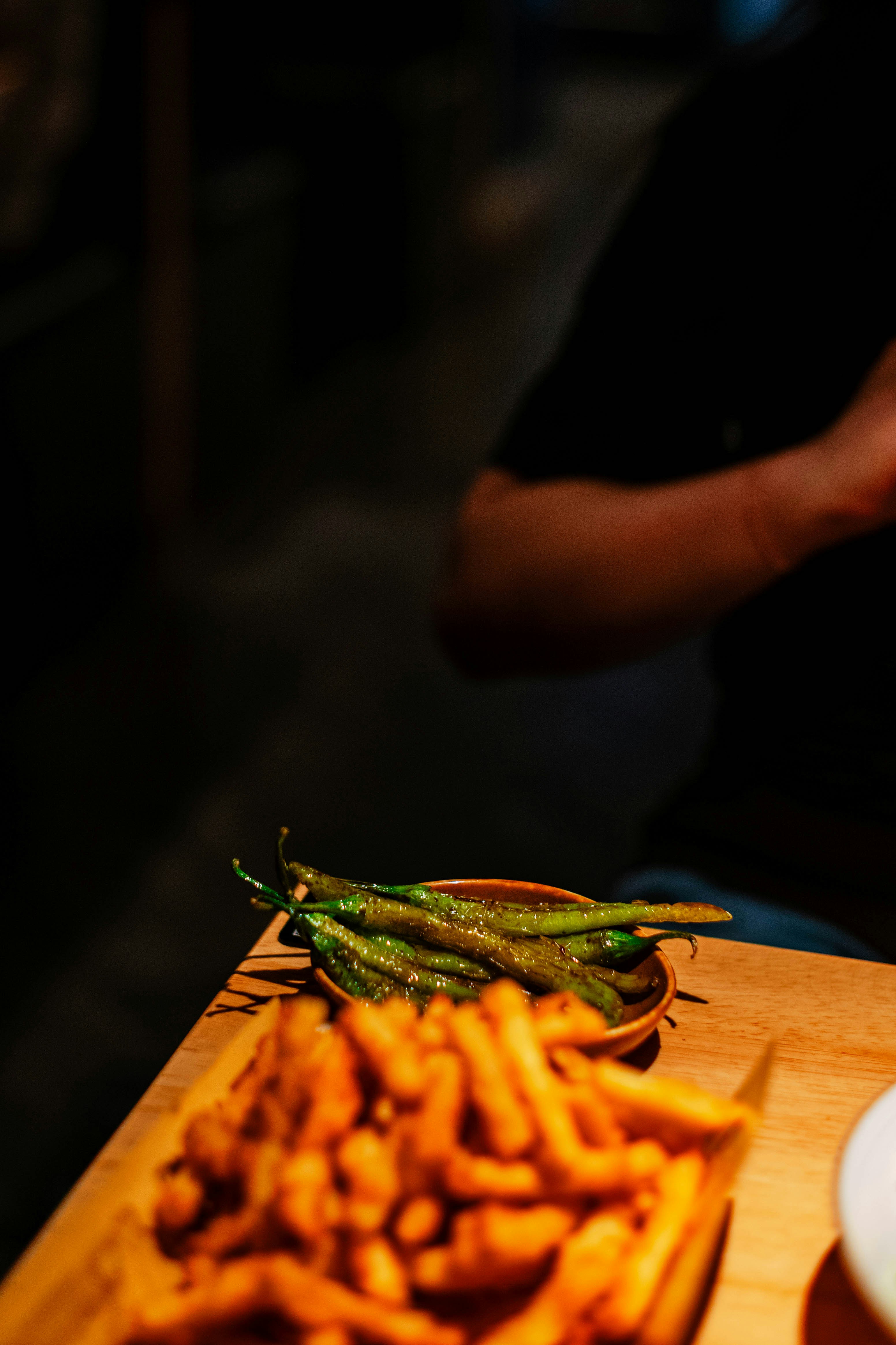 Fries and green beans on a wooden table.
