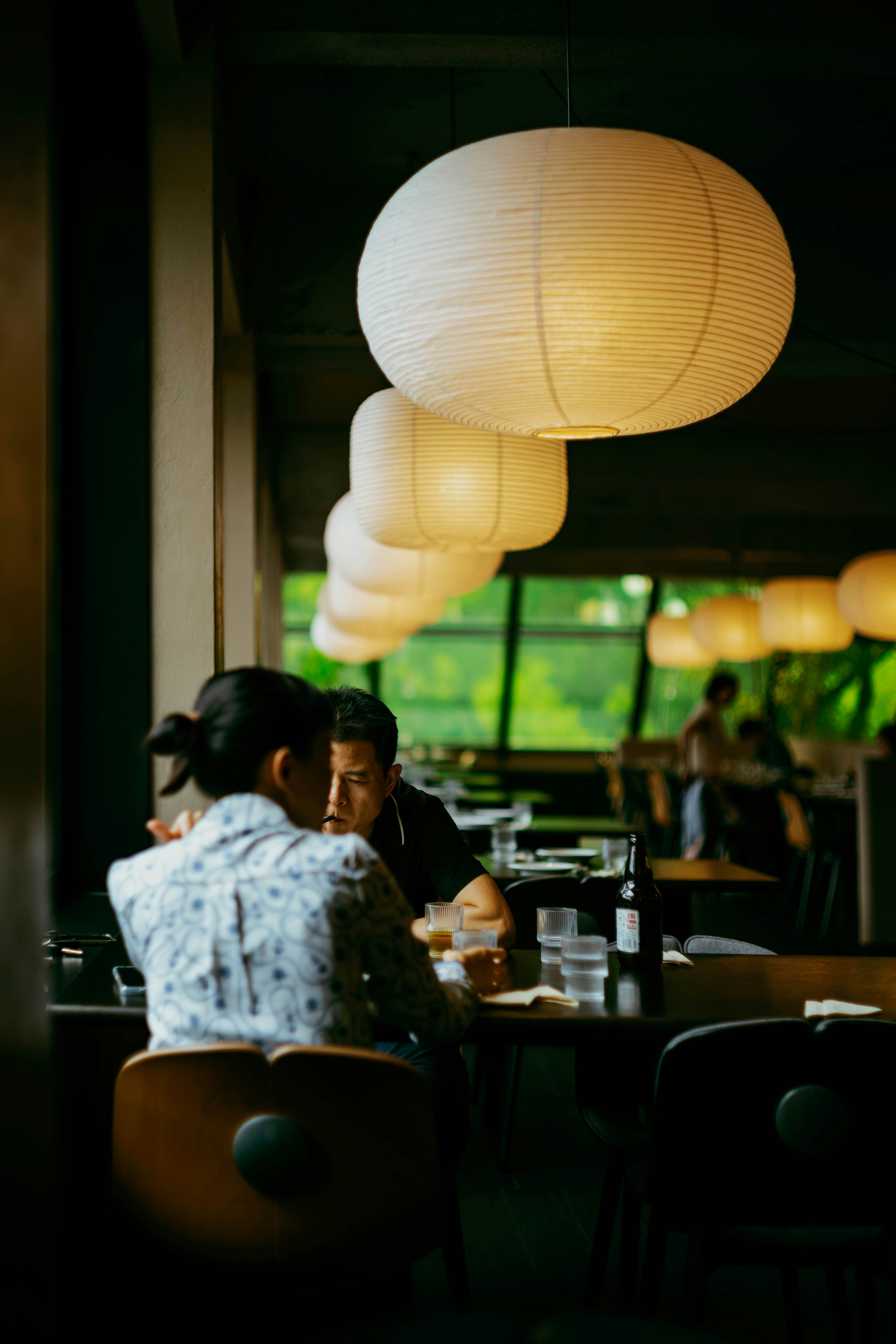 People dine under hanging paper lanterns.