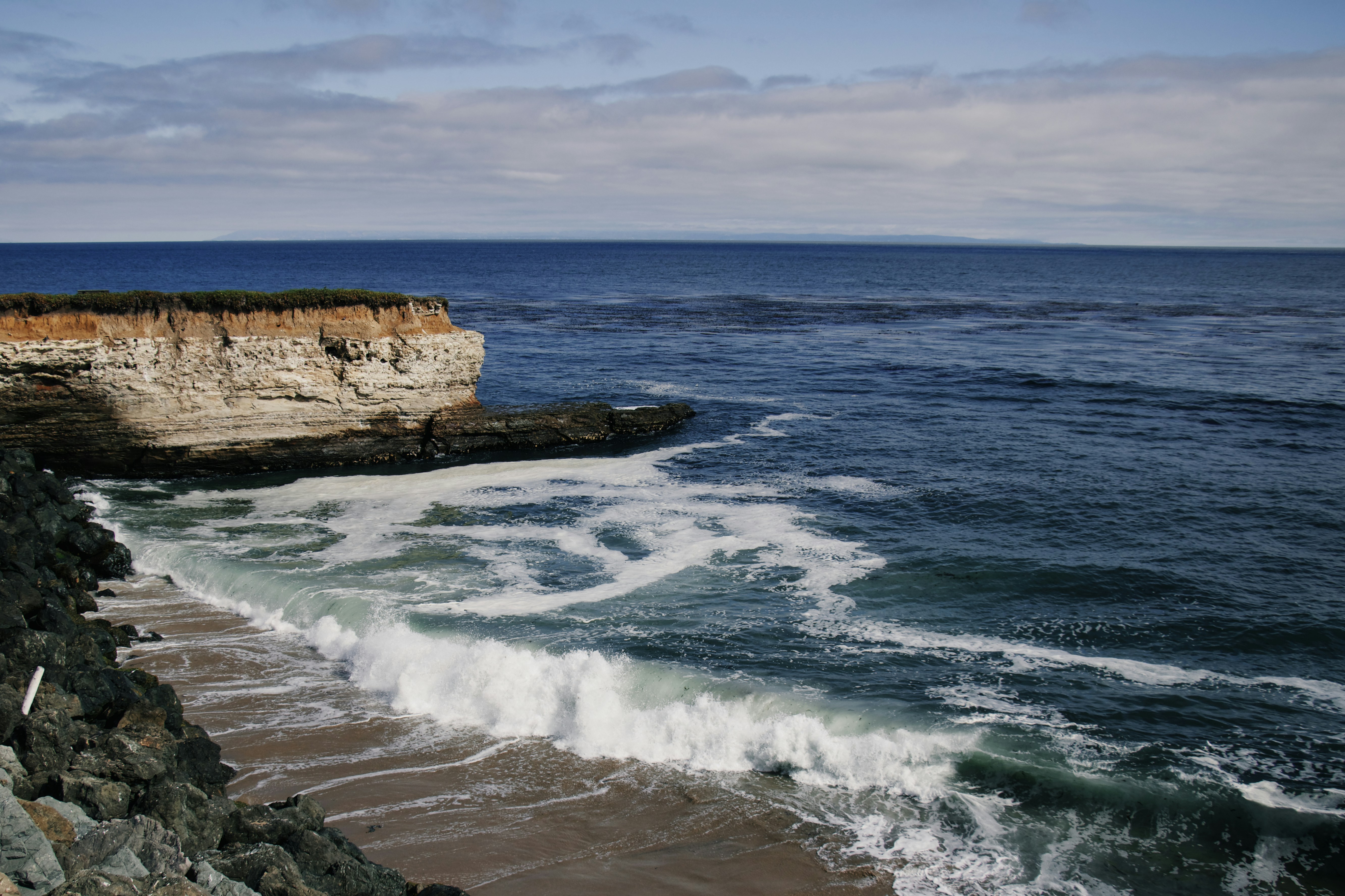 Waves crash on a rocky shore near cliffs.