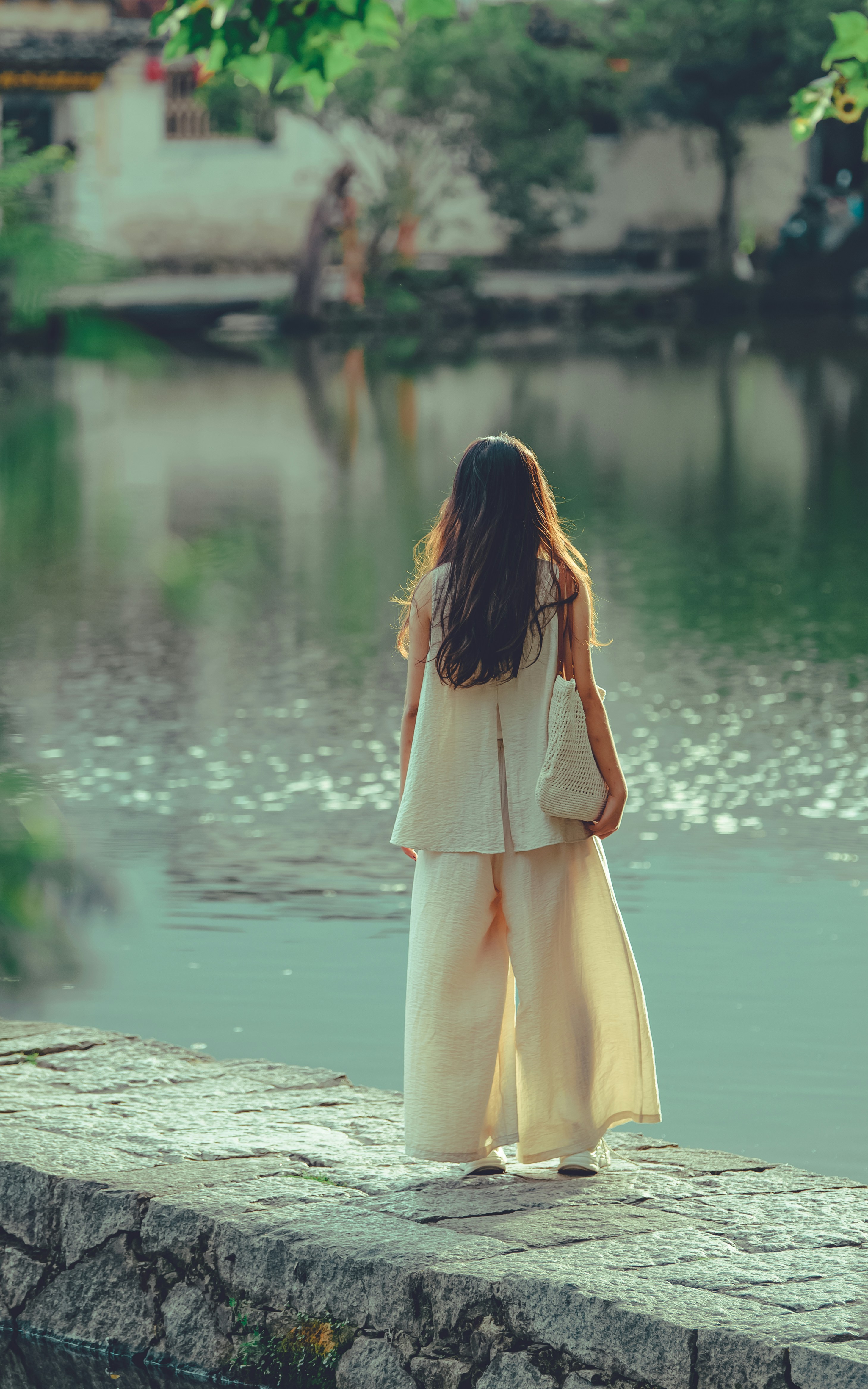 The girl on the bridge | Woman gazing at a calm lake in the sunshine.