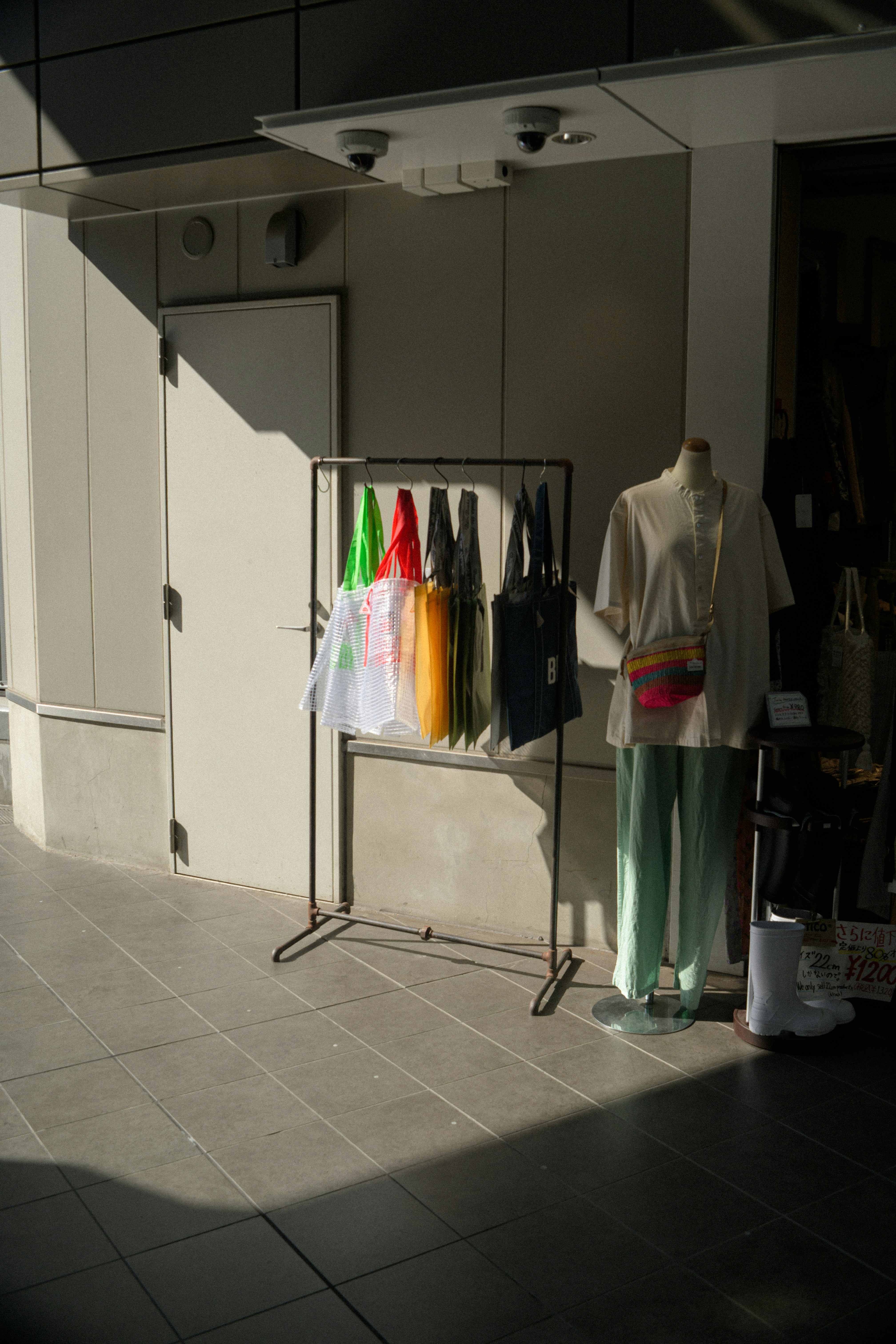 Colorful bags displayed outside a shop on a sunny day.