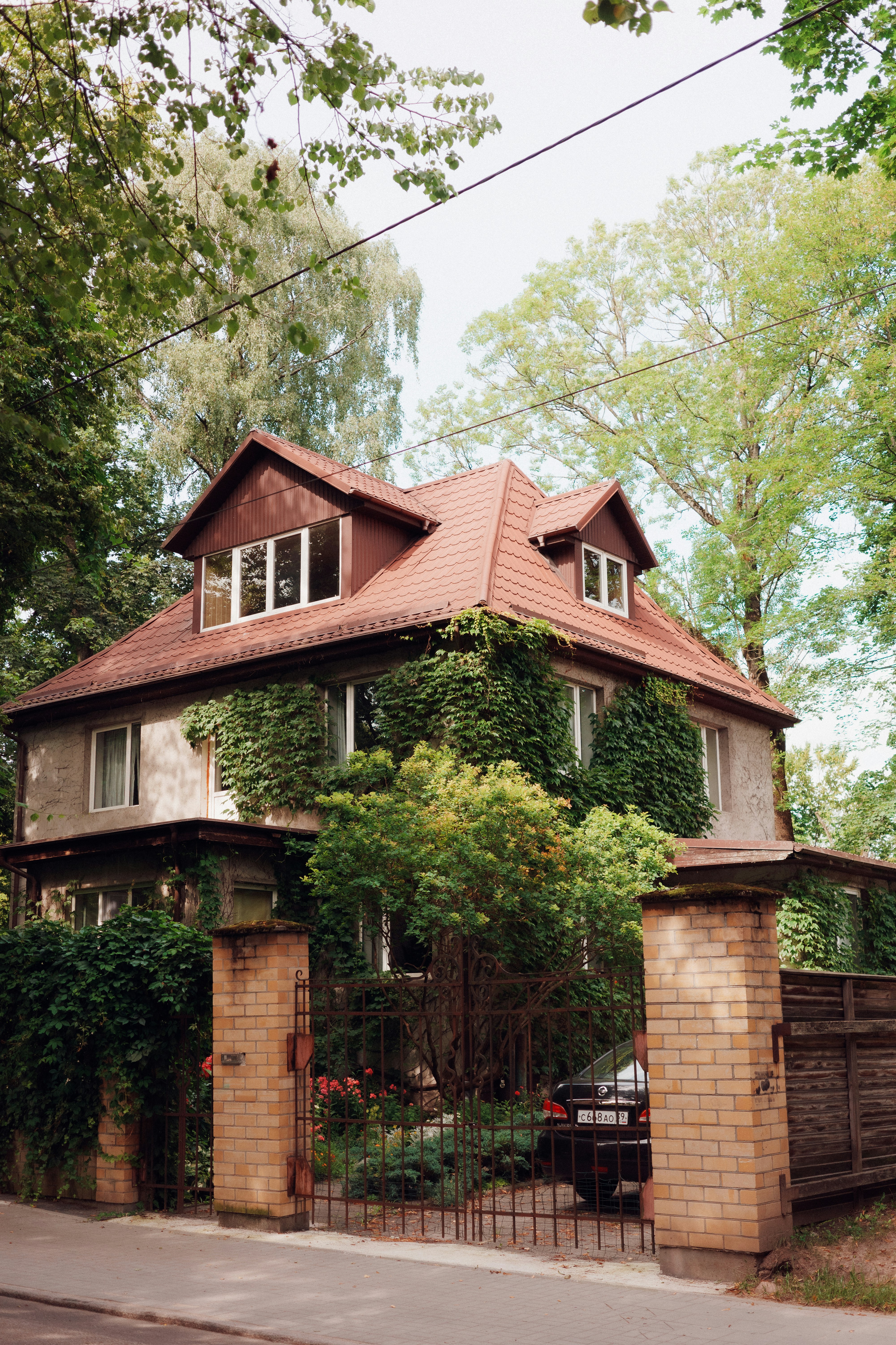 Ivy-covered house with a red roof and brick pillars.