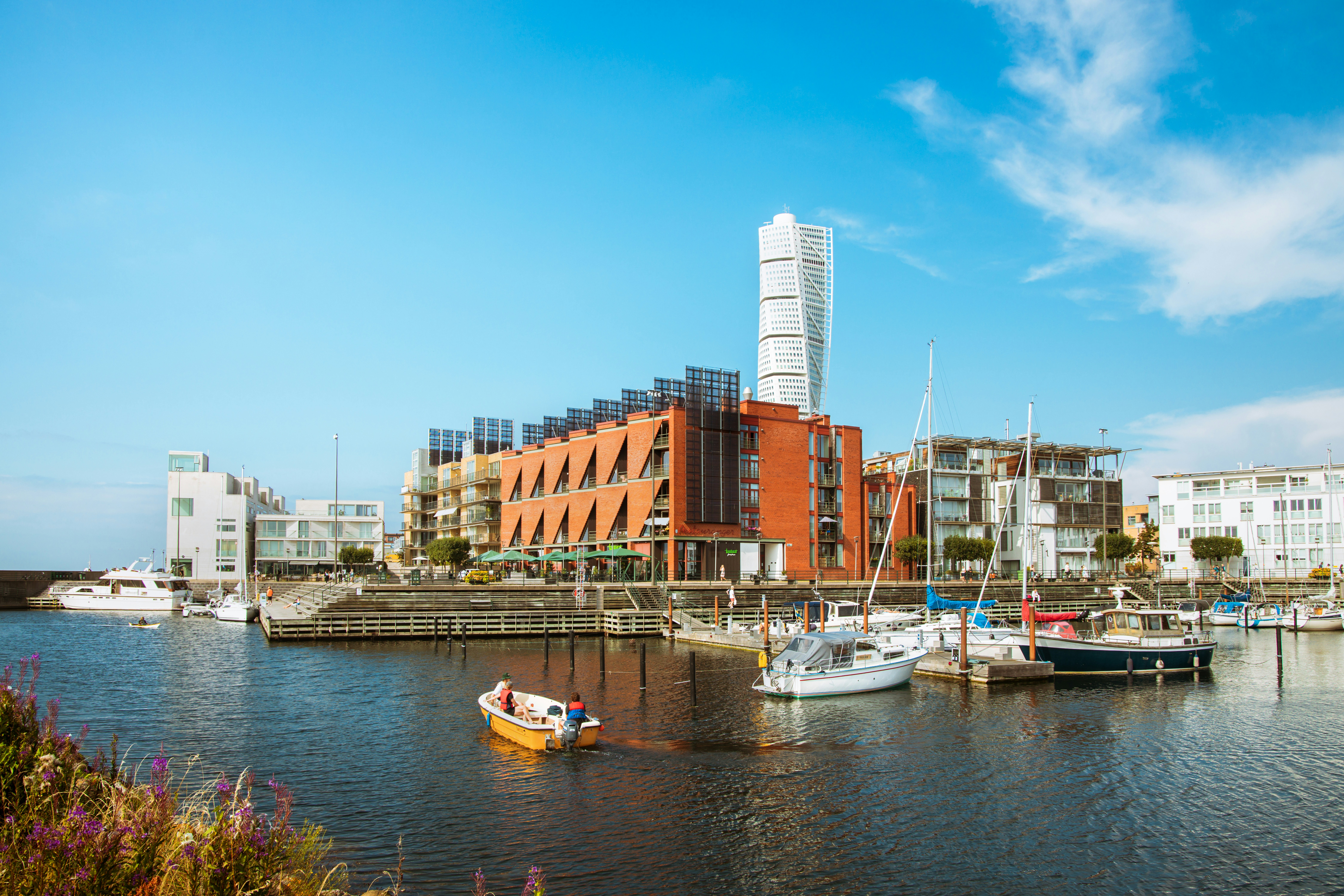 Vibrant waterfront scene showcasing contemporary buildings alongside moored boats in a serene harbor setting.