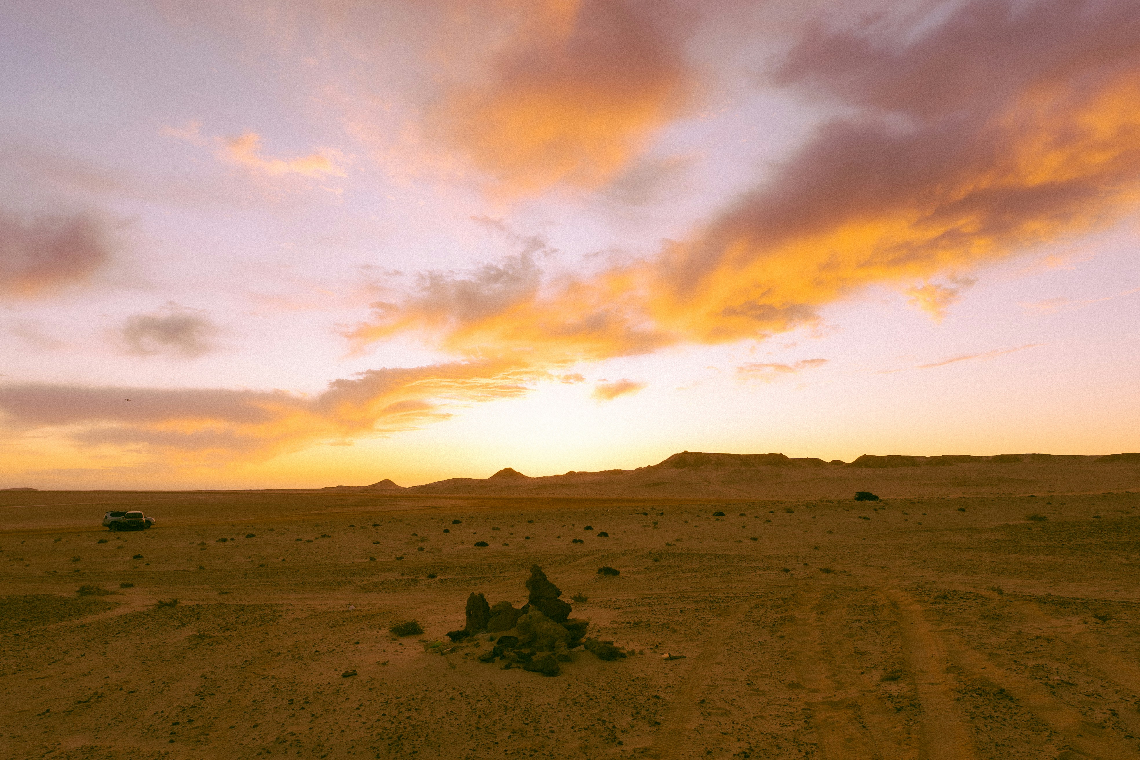 Sunset illuminates a desert landscape with vehicles.