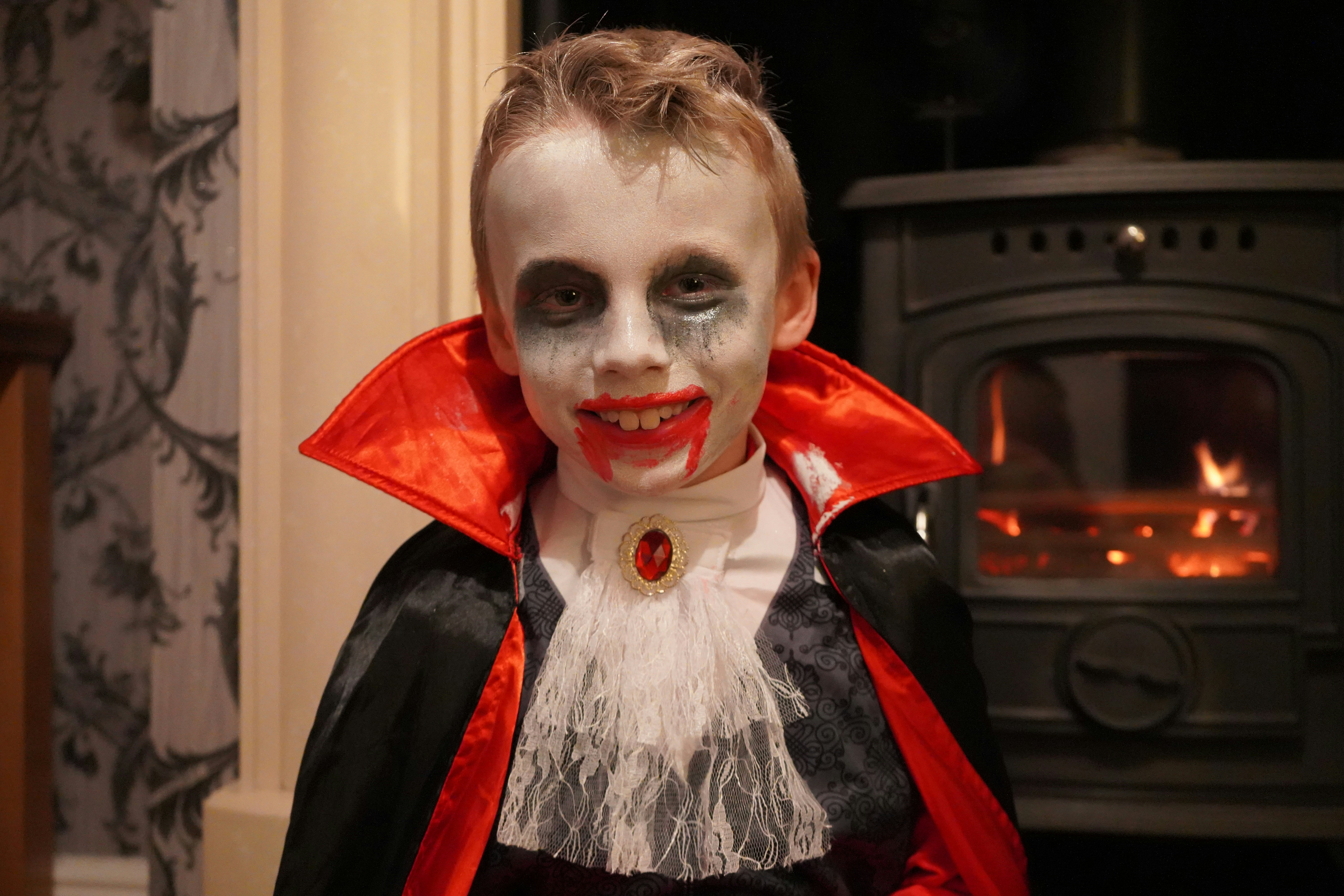 A young boy dressed in a vampire costume.