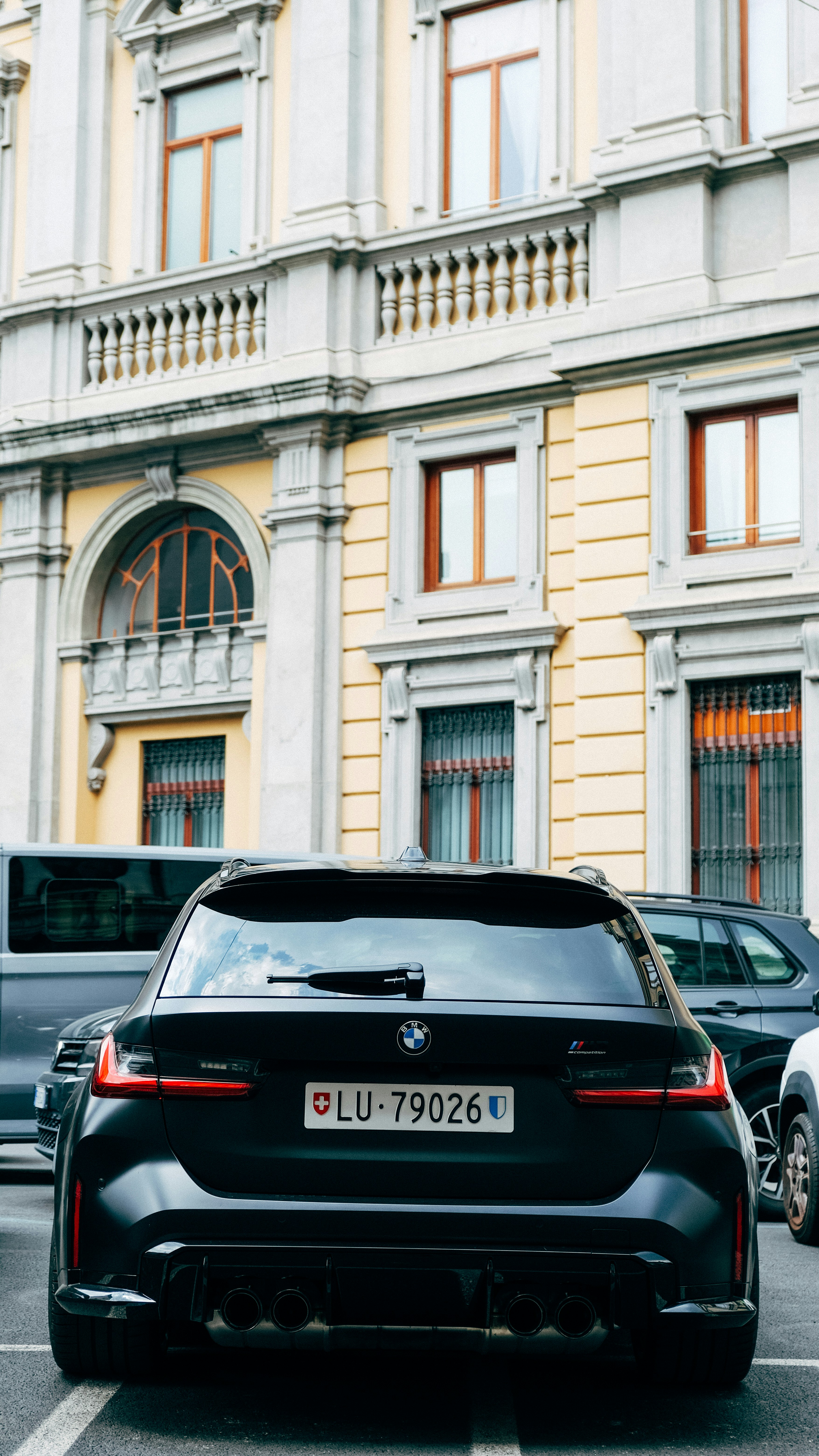 A black BMW is parked in front of a building.