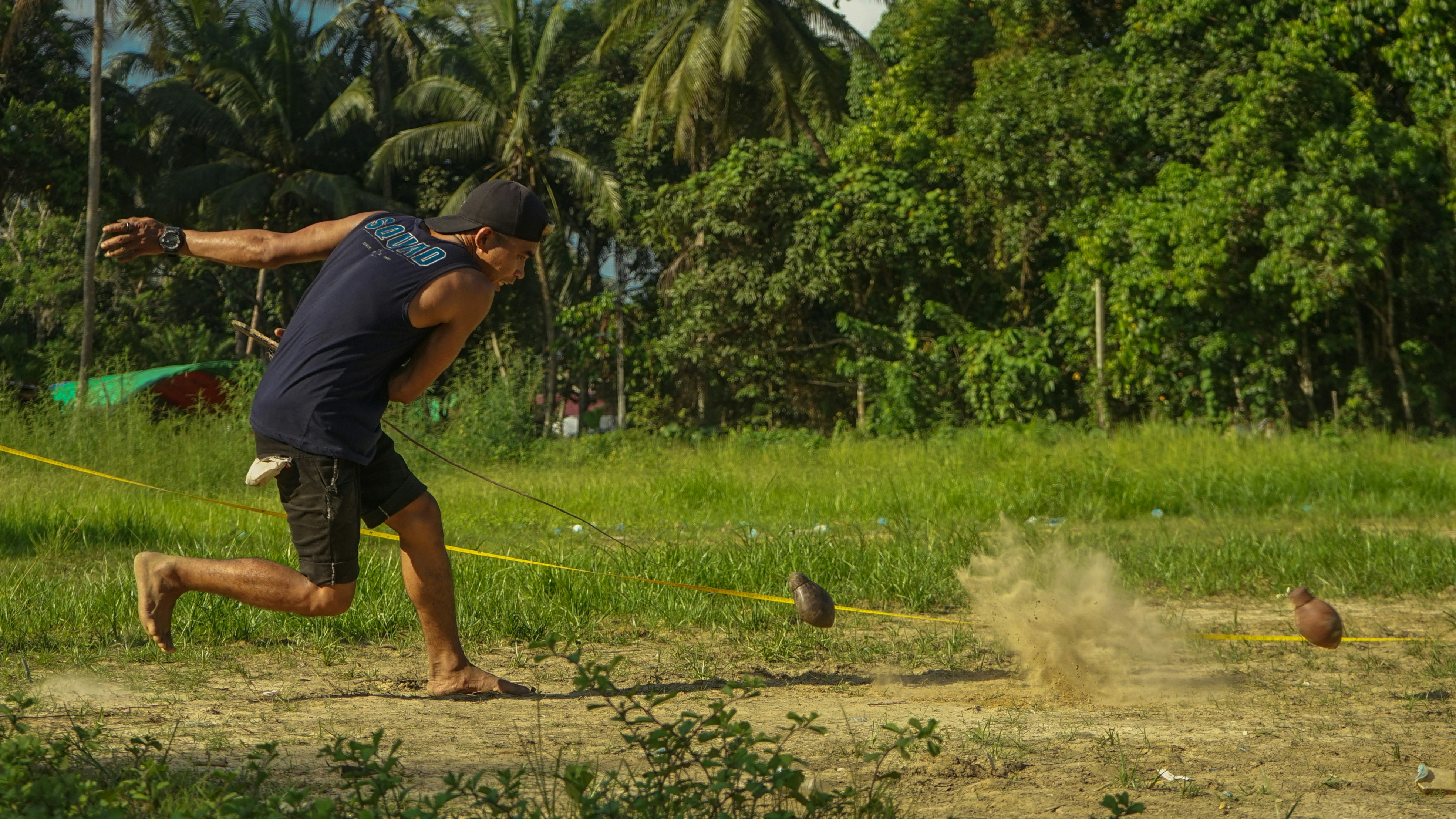 A man playing traditional game called 'Gasing' | A man throws something in a field.