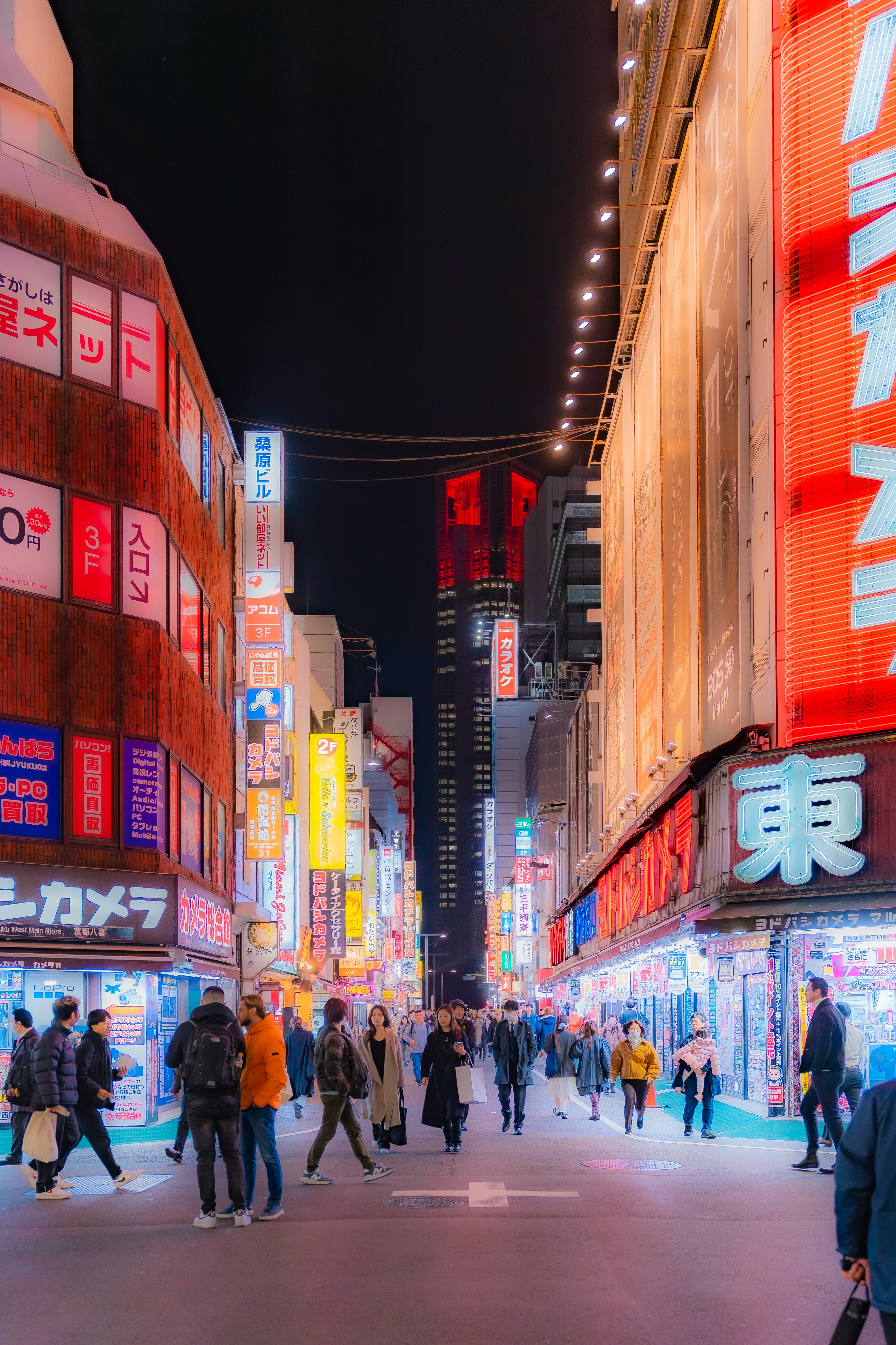 A busy street in a brightly lit city at night.