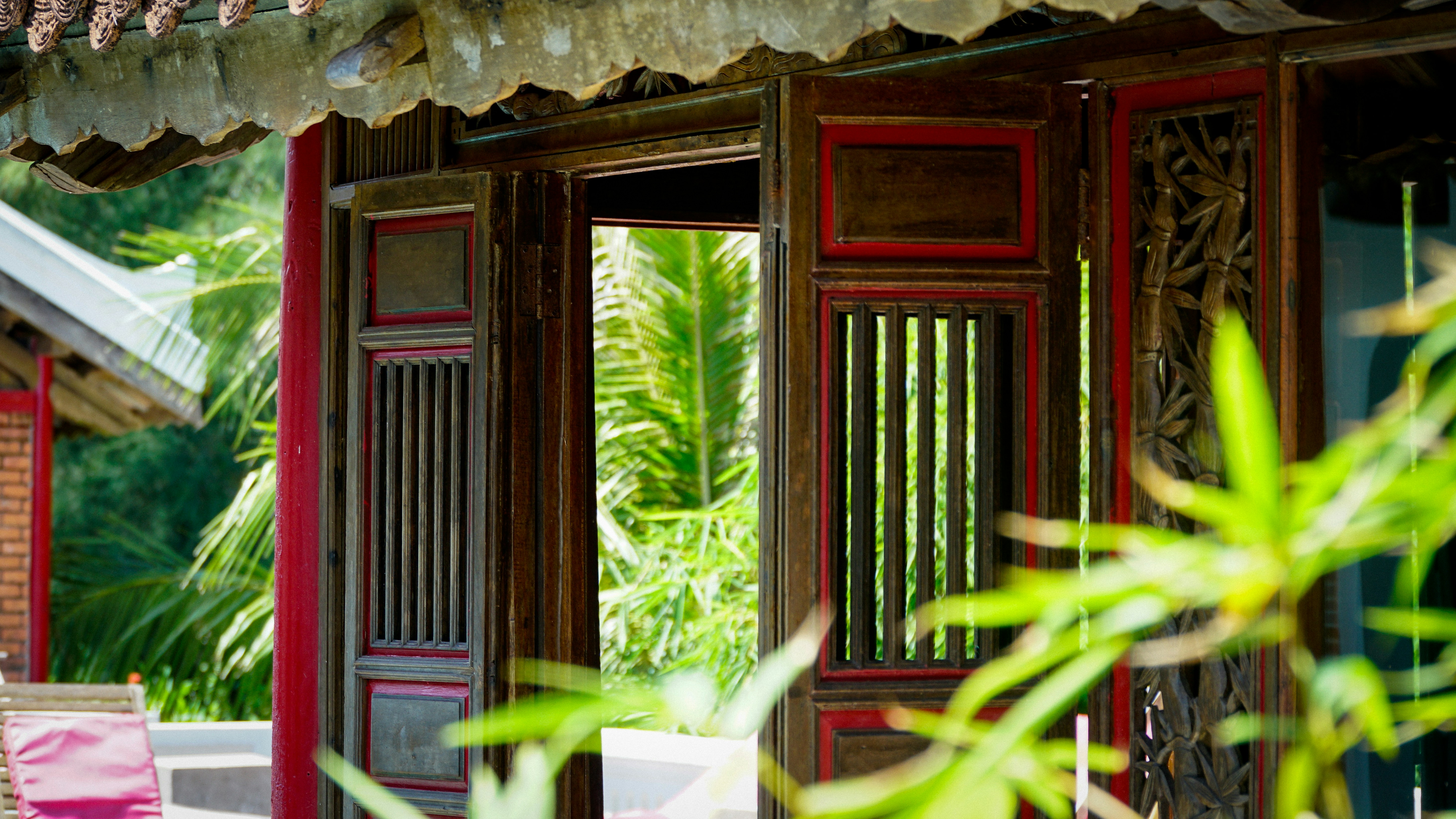 Intricate wooden architecture framed by lush greenery, inviting a glimpse into a tranquil retreat.
