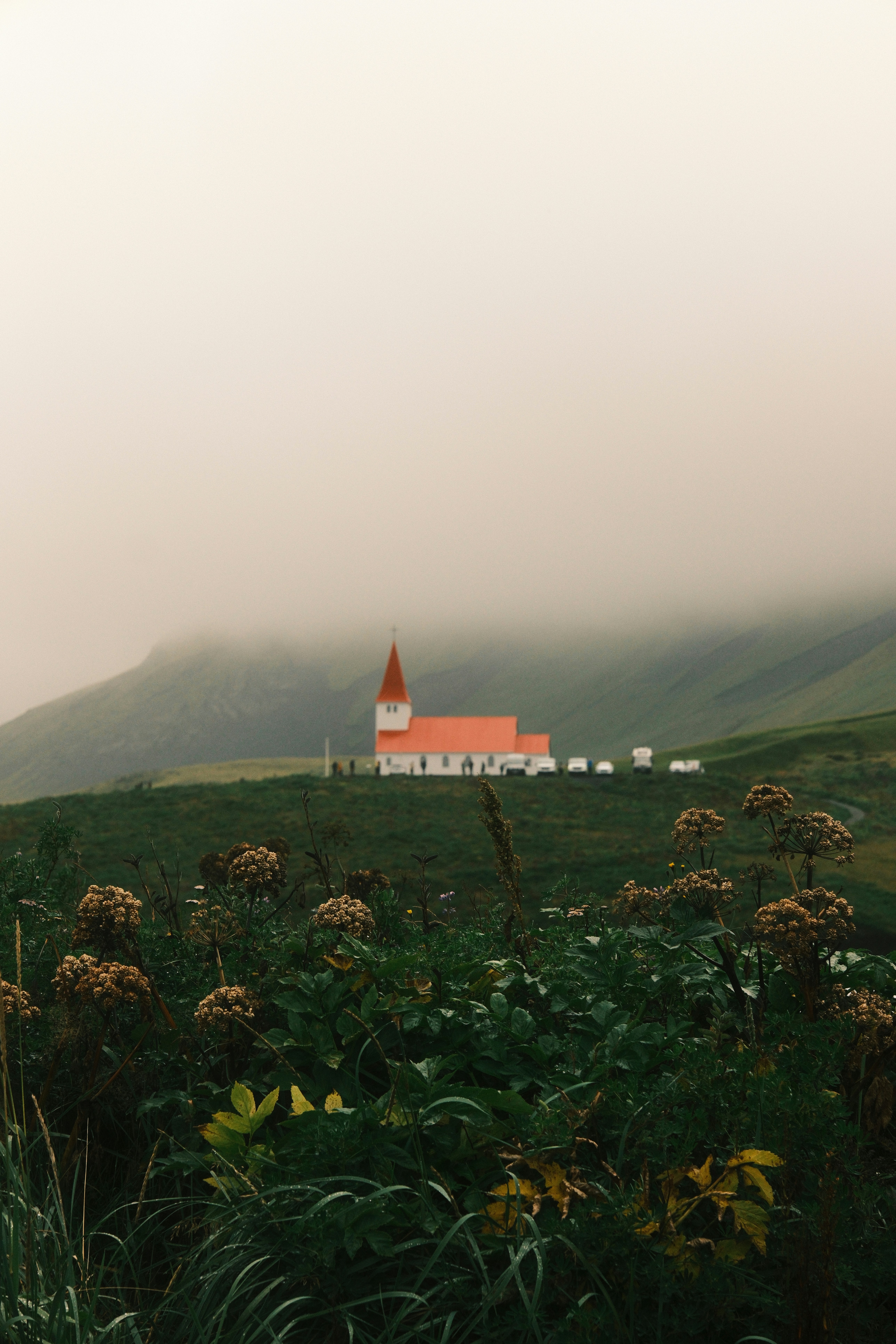 The church of Vik, on a foggy summers day in Iceland | A church sits on a misty green hillside.