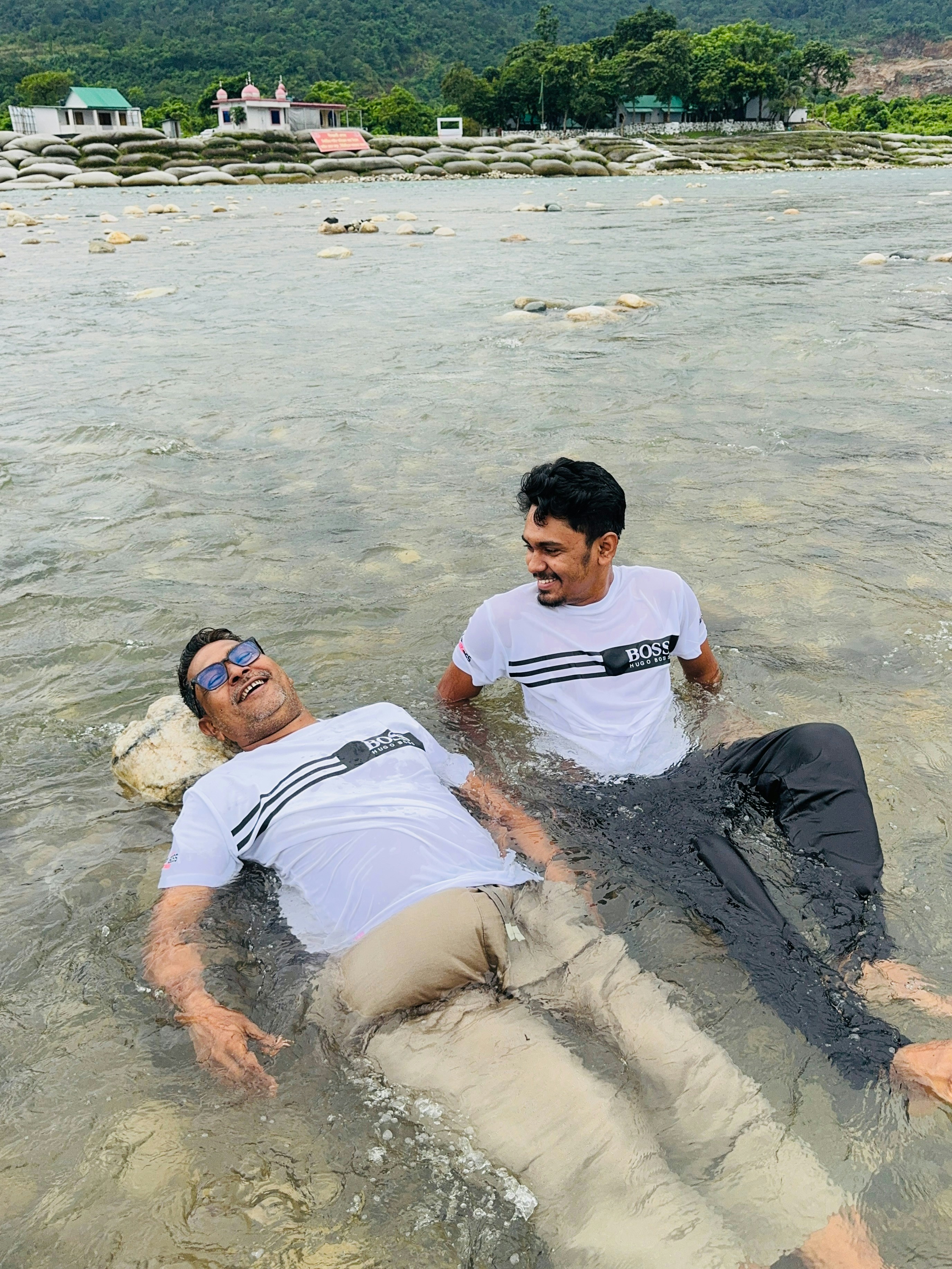 Two men relax in shallow river water. photo – Free Travel Image on Unsplash