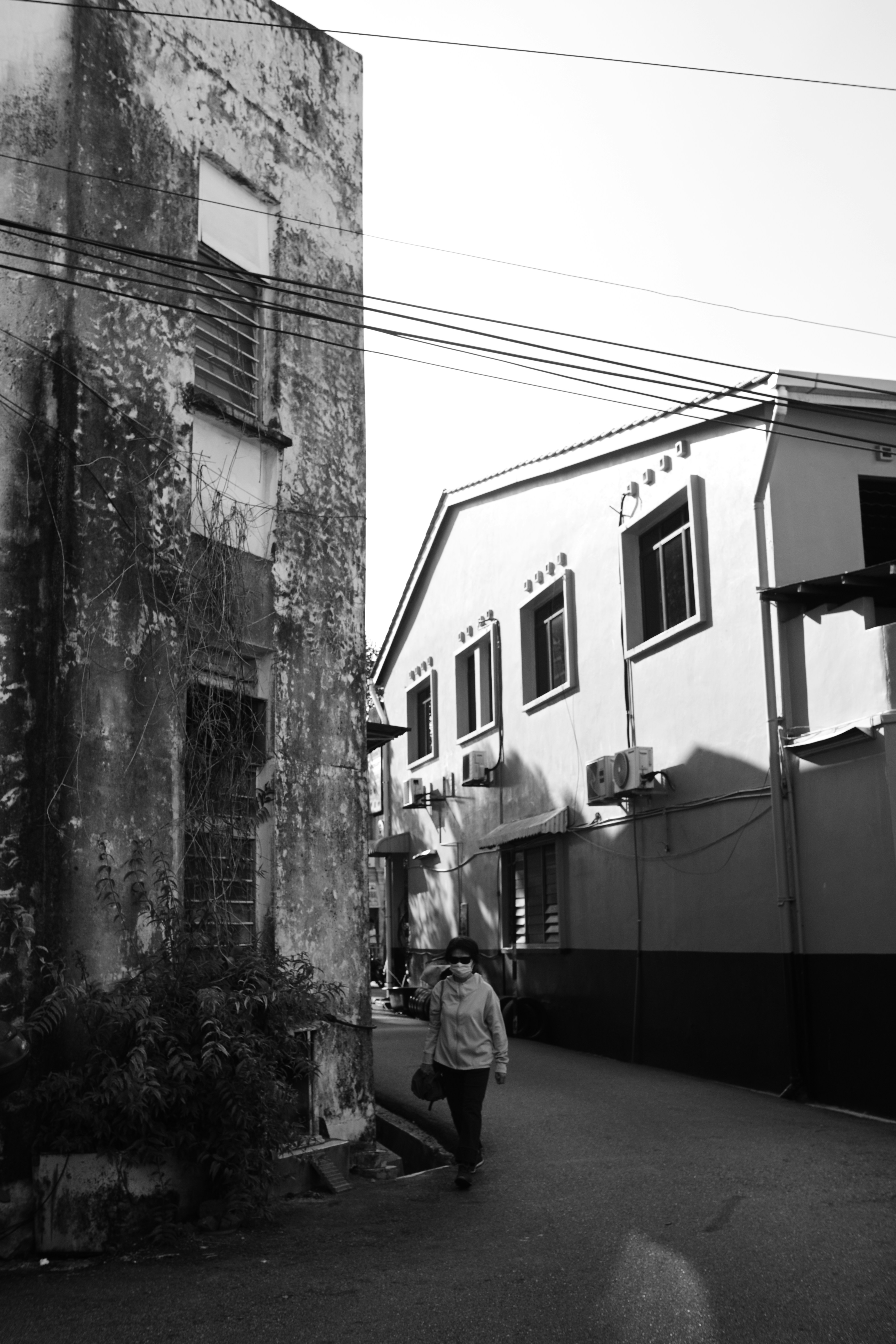 A solitary figure walks down a narrow street flanked by weathered buildings, capturing the essence of urban solitude and history.