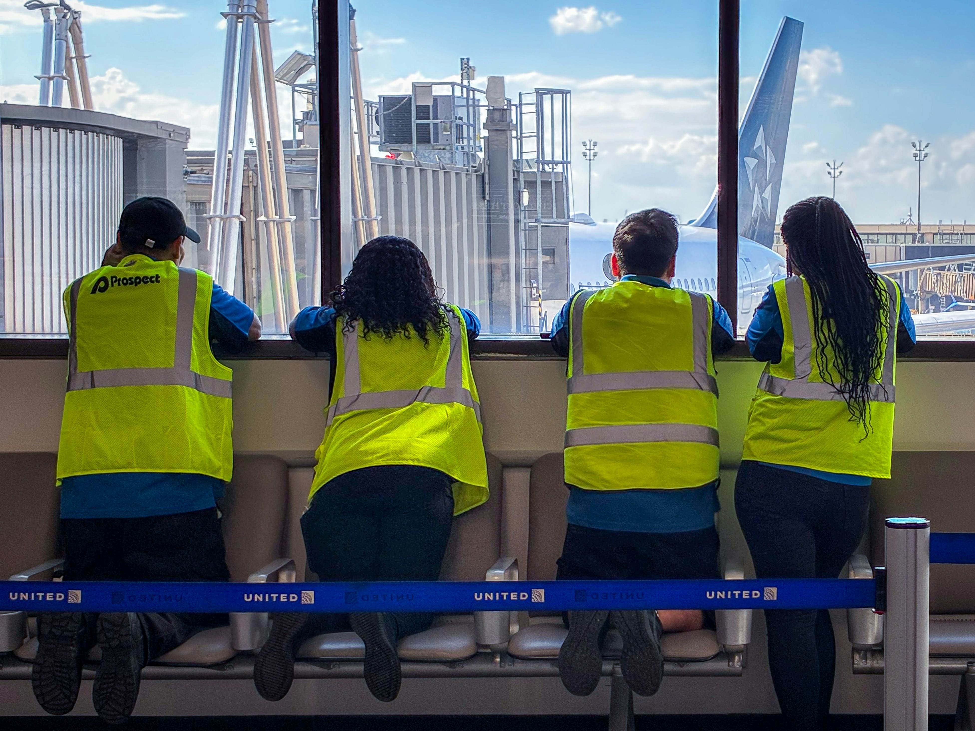 Safety first. | Airport employees watch planes through a window.