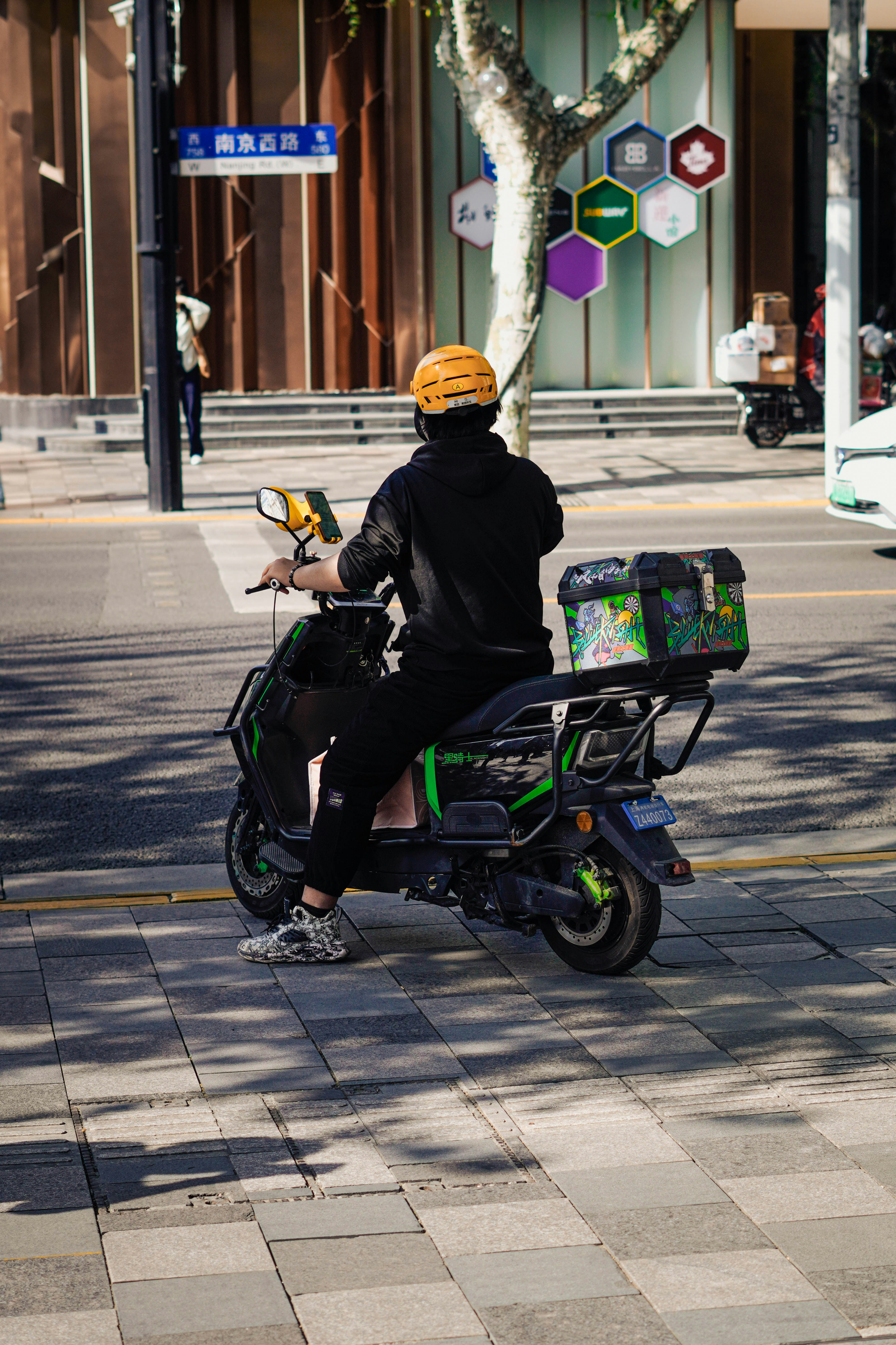 A delivery driver sits on a scooter.