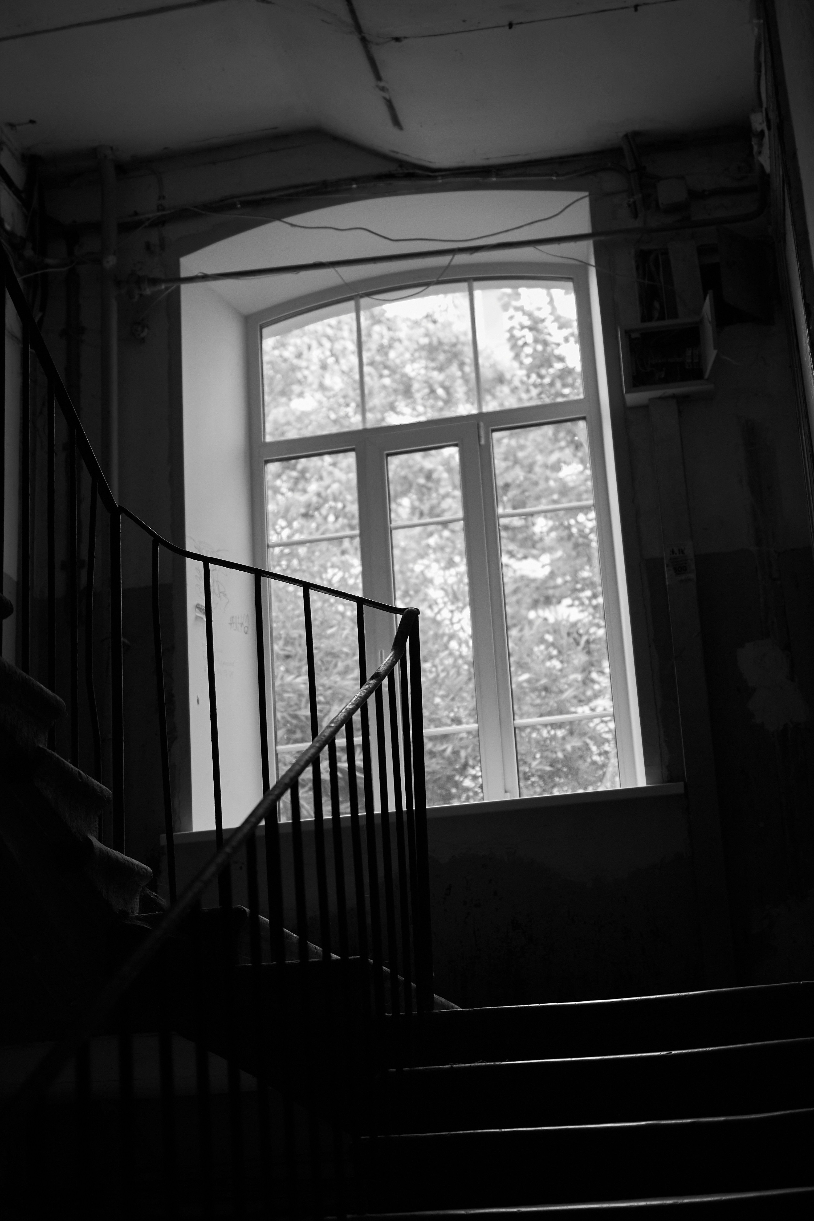 Staircase leads toward a bright window in black and white.