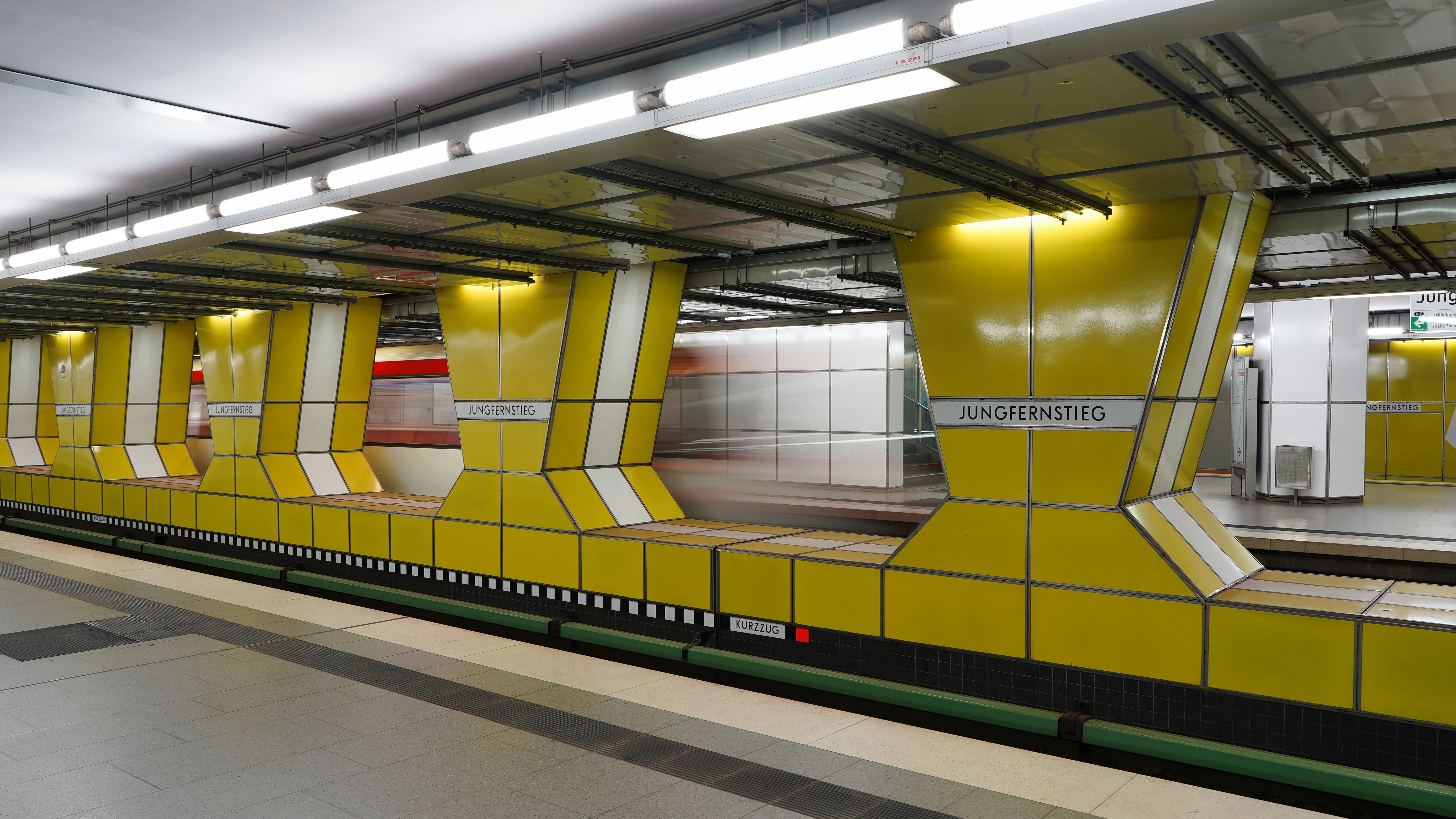 Vibrant yellow pillars and sleek lines create a modern aesthetic in the Jungfernstieg subway station, showcasing urban design elements. The scene captures the essence of contemporary transit architecture.