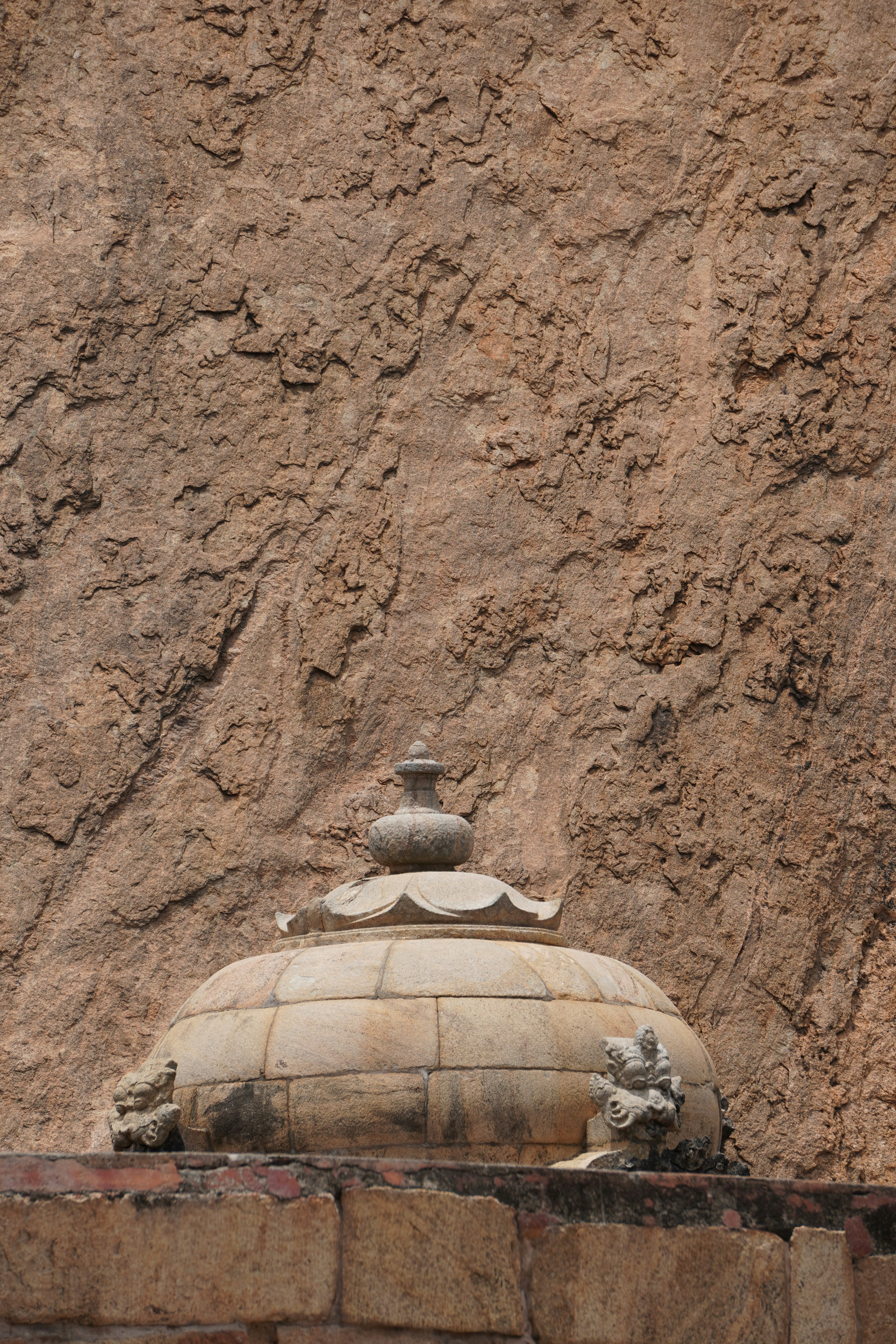 Kadambar Kovil | A stone dome sits against a textured wall.