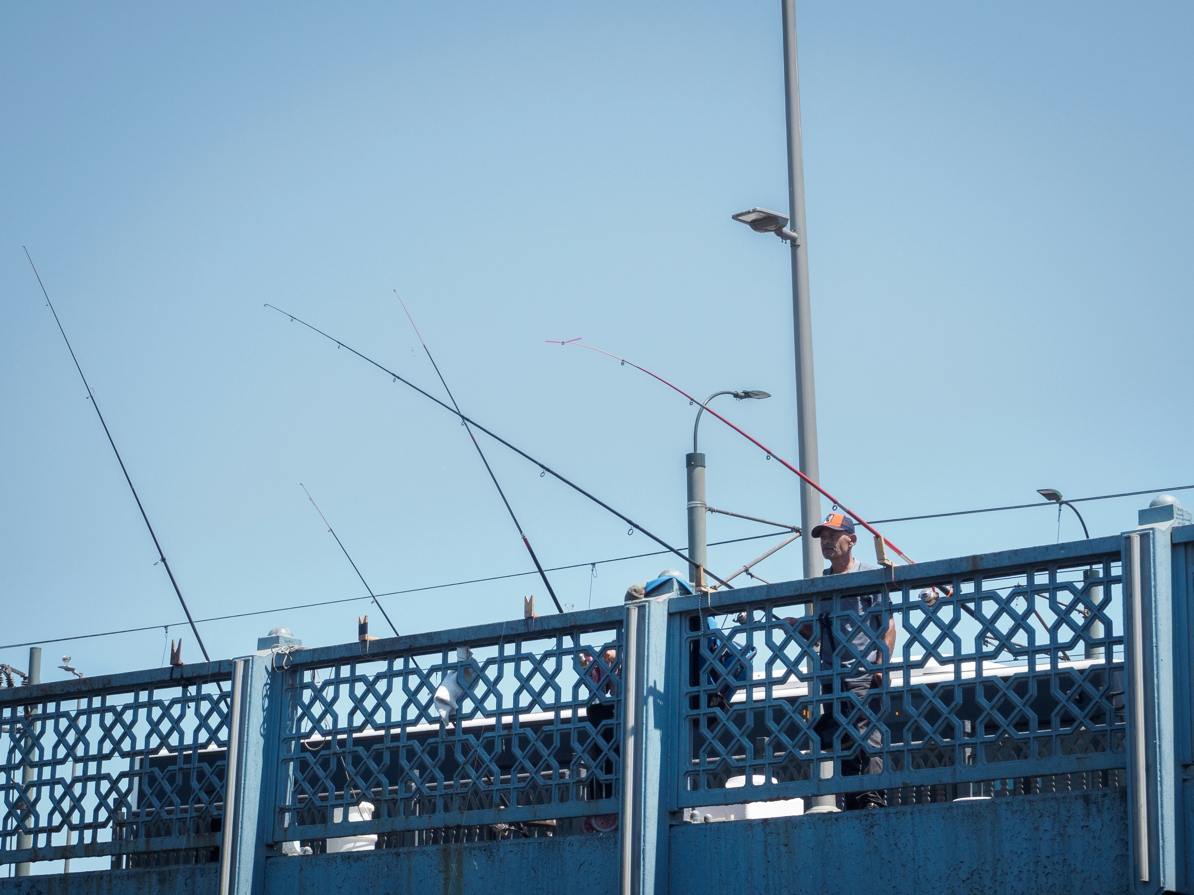People are fishing from a bridge with fishing rods.