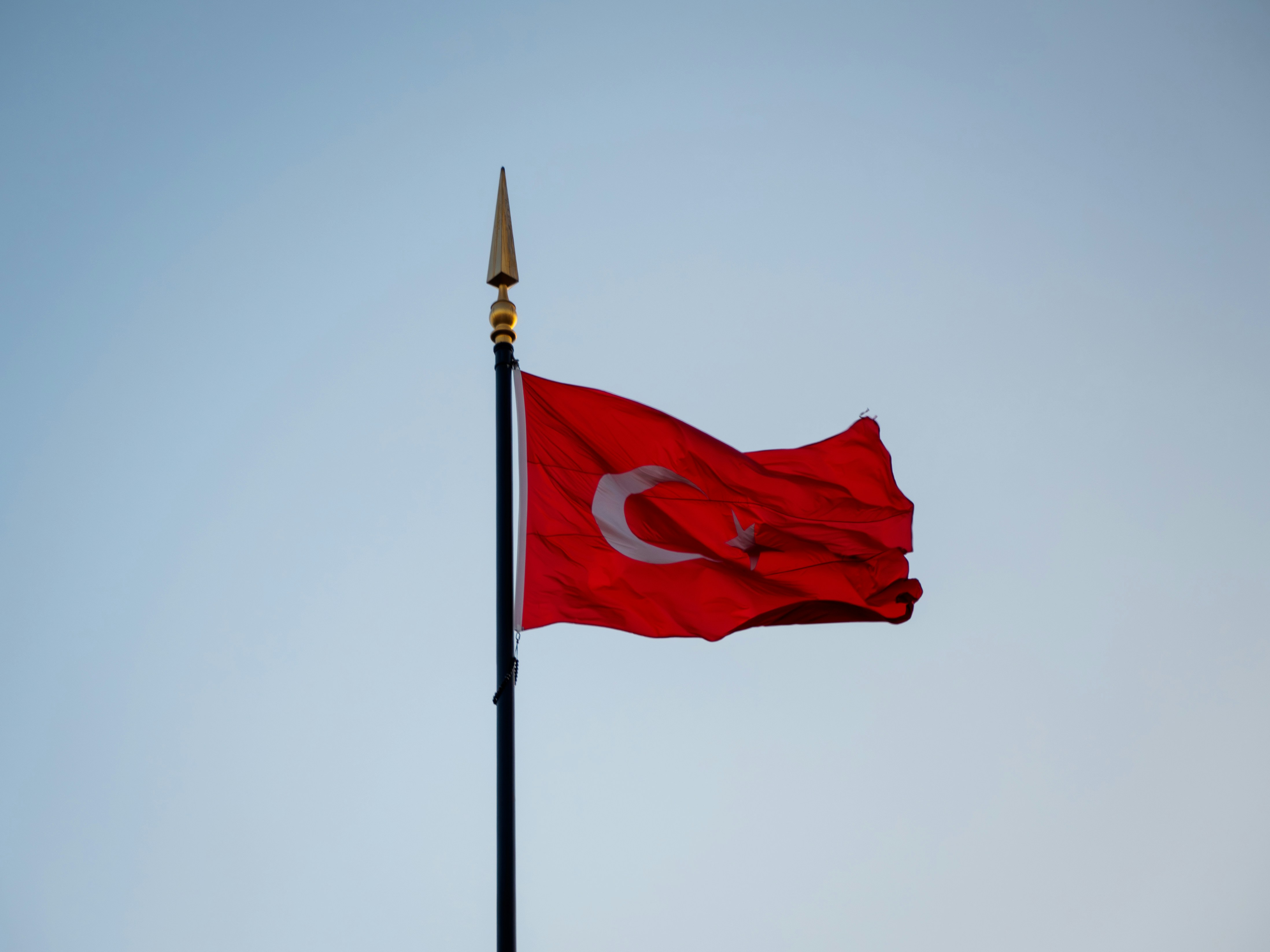 The turkish flag waves in the sky.