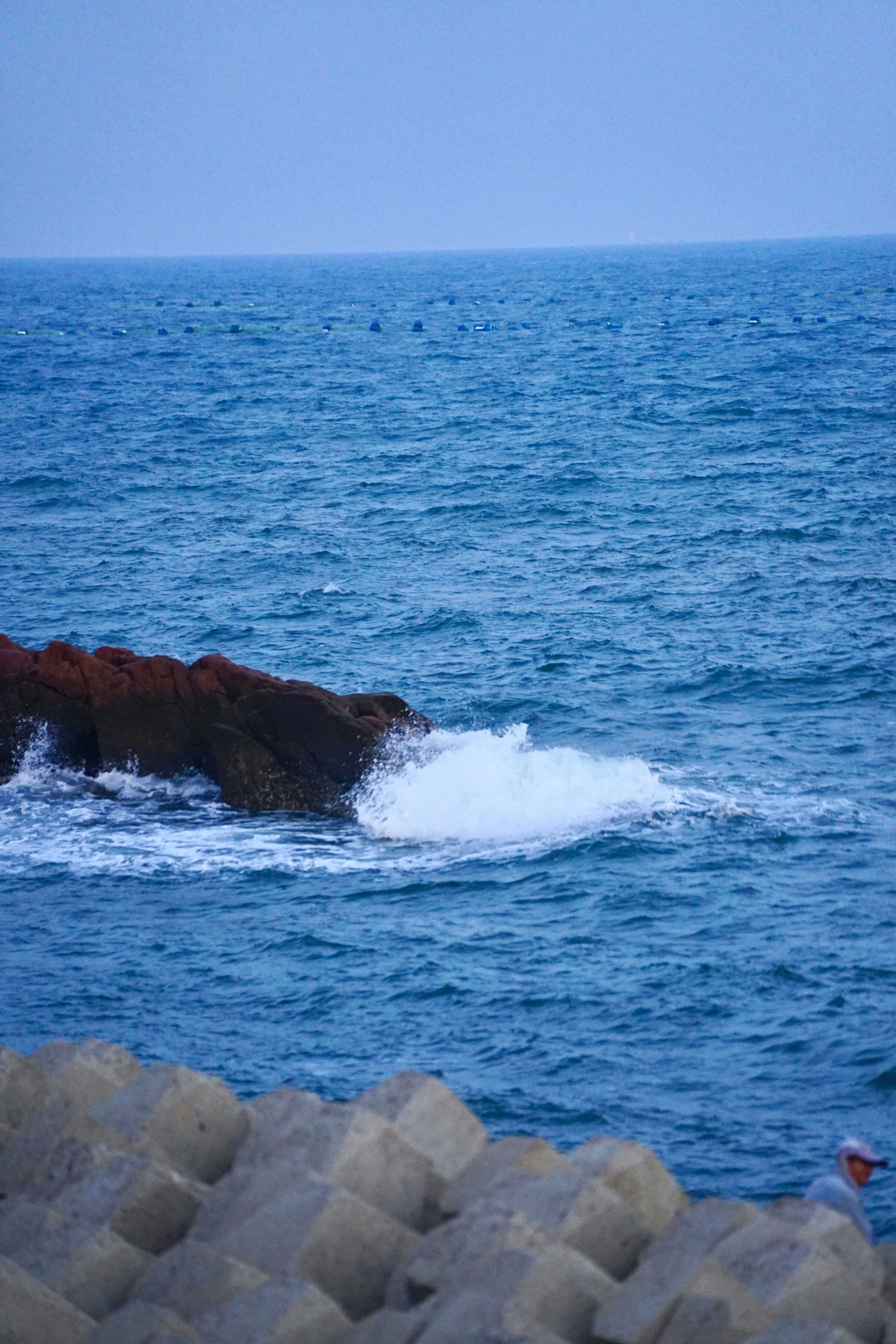Waves crash against a rocky coast at dusk.