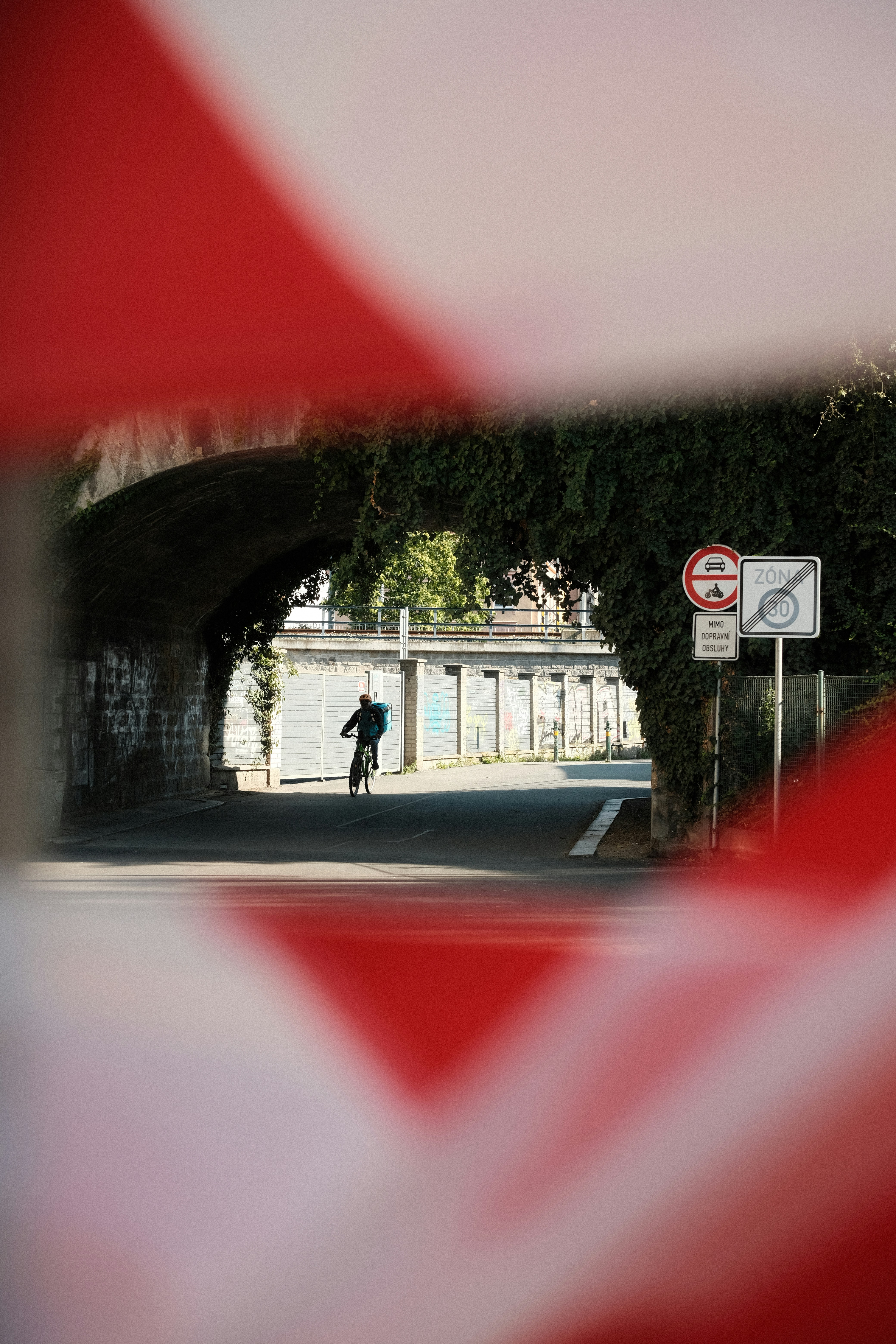 Bicycle rider under an archway in a city setting | A cyclist rides underneath an overpass.