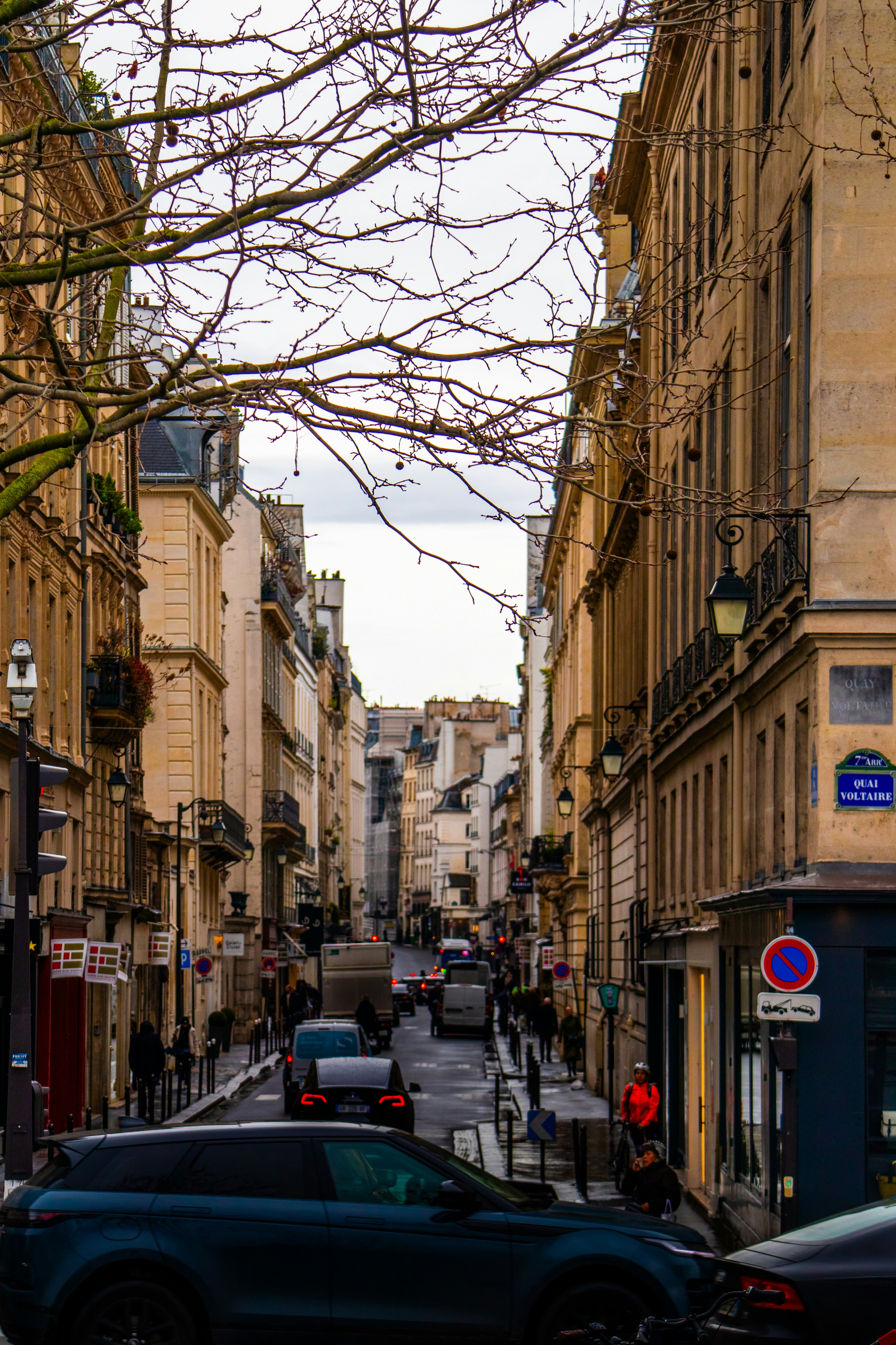 Narrow Parisian street lined with classic architecture, featuring vehicles and pedestrians amidst a tranquil urban atmosphere.