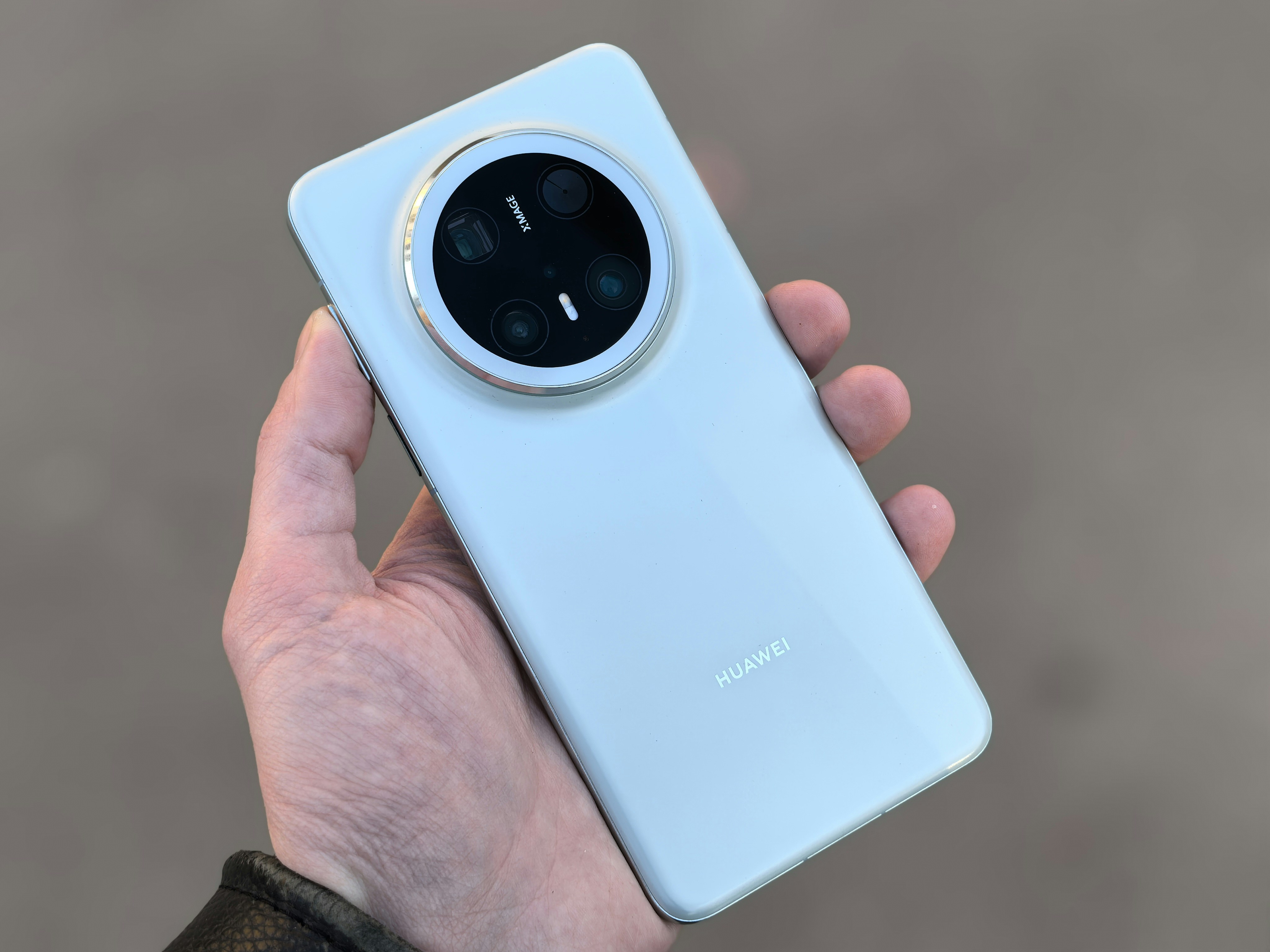 Close-up view of a Huawei Pura 70 Ultra smartphone held in a hand, showcasing its sleek design and distinctive camera module.