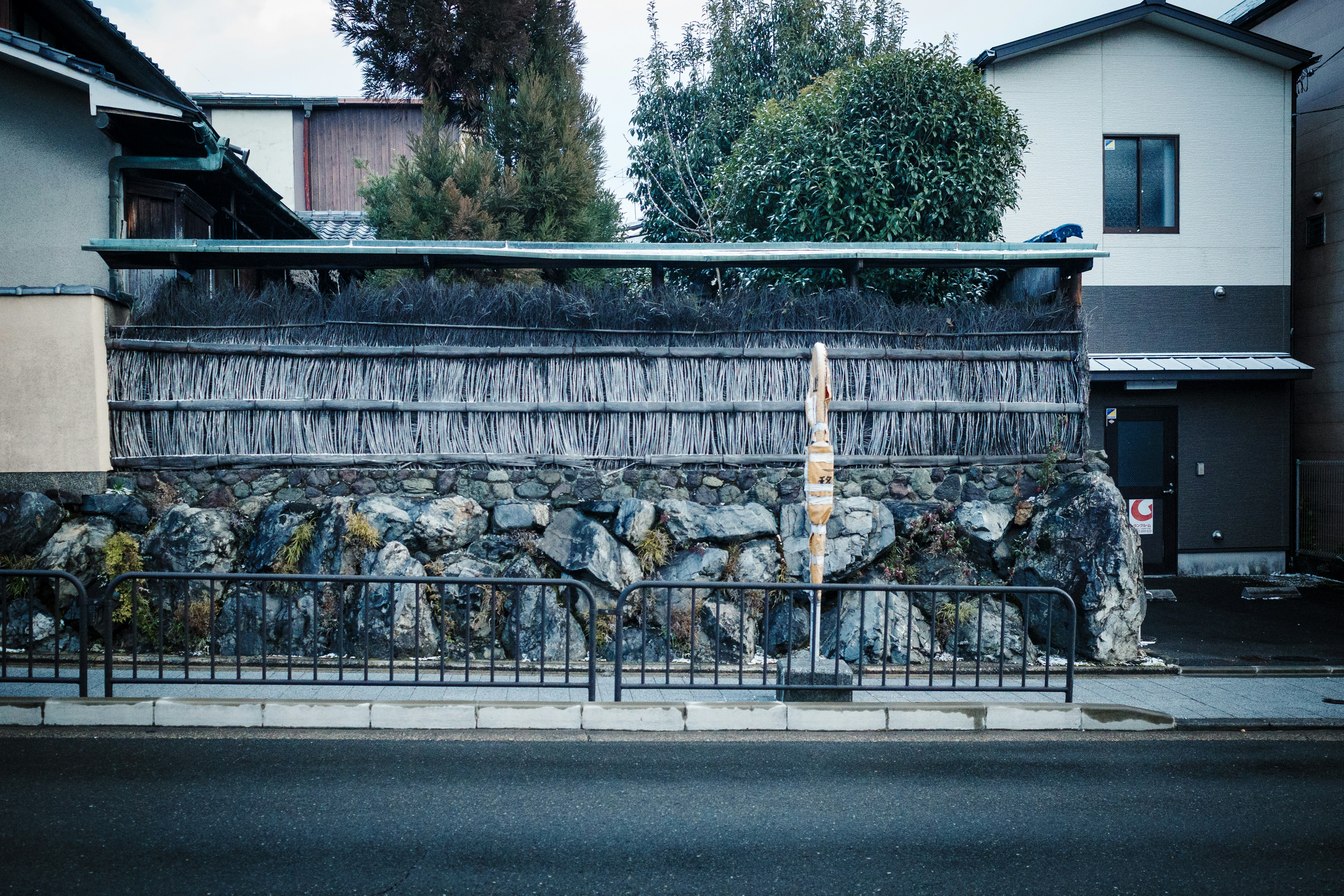Marker on a Stone Wall: Quiet Streetfront Framed by Weathered Wood