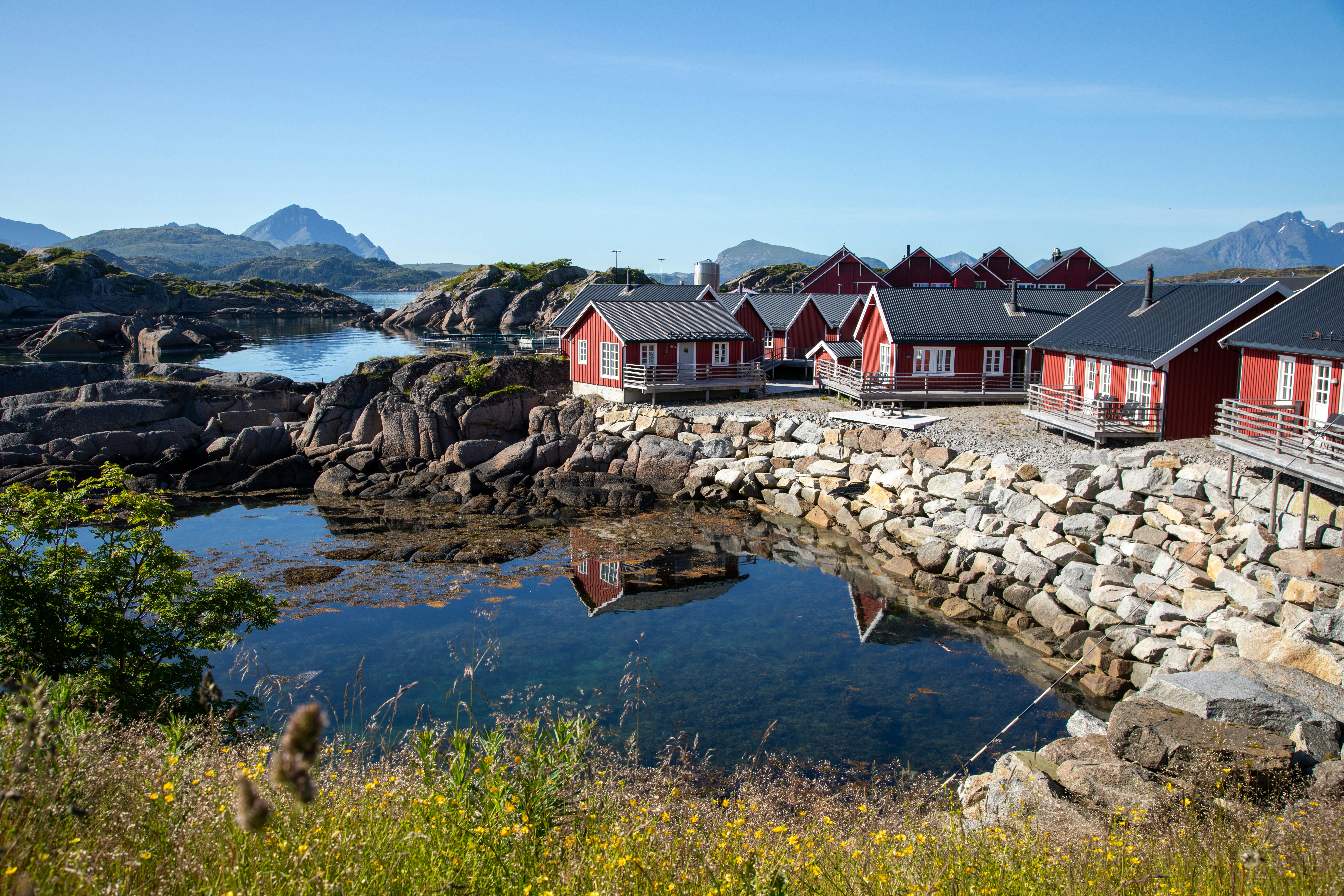 Red Seaside Village: Sturdy Docks and Red Cabins Against Rocky Fjord