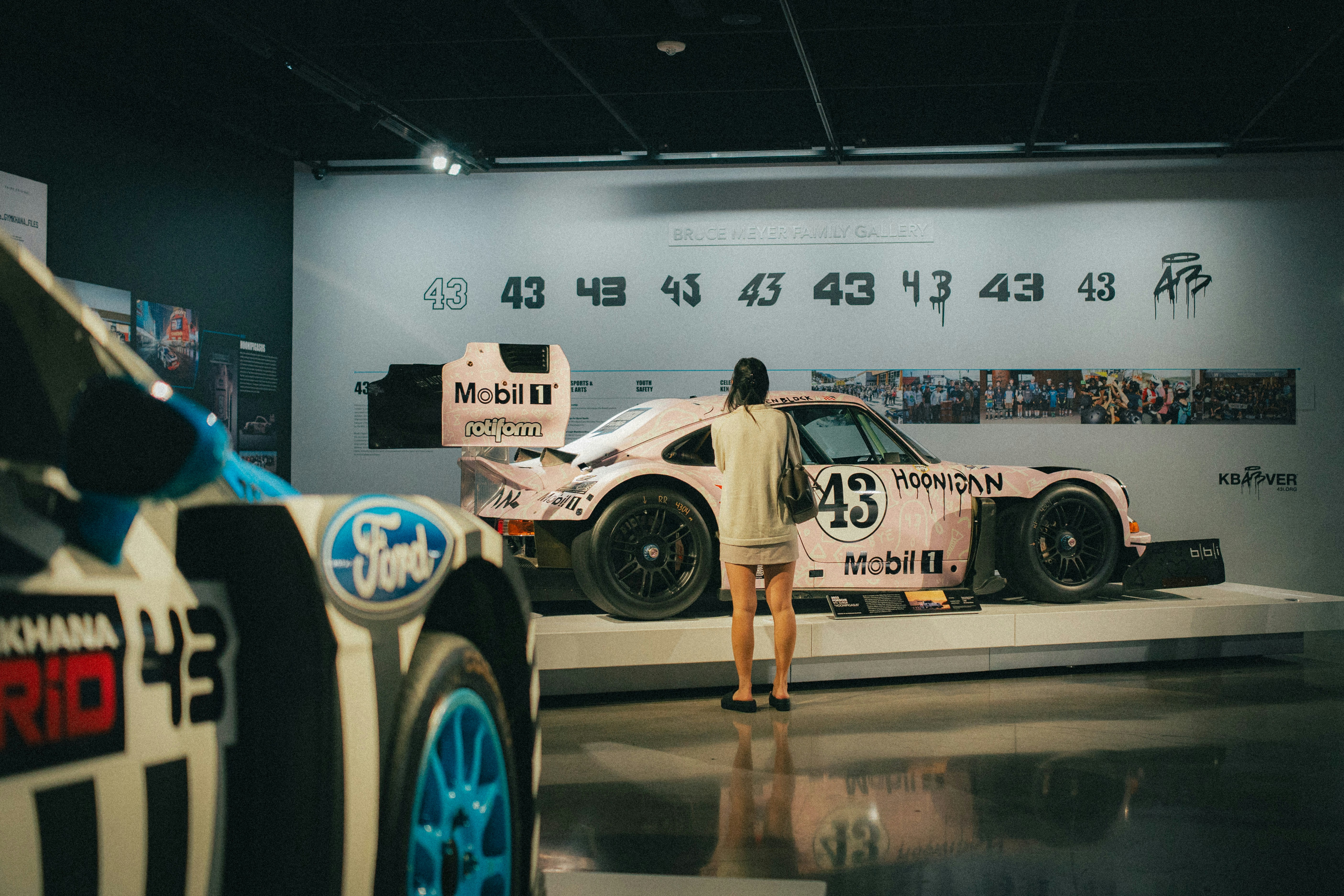 A woman admires a race car in a museum.
