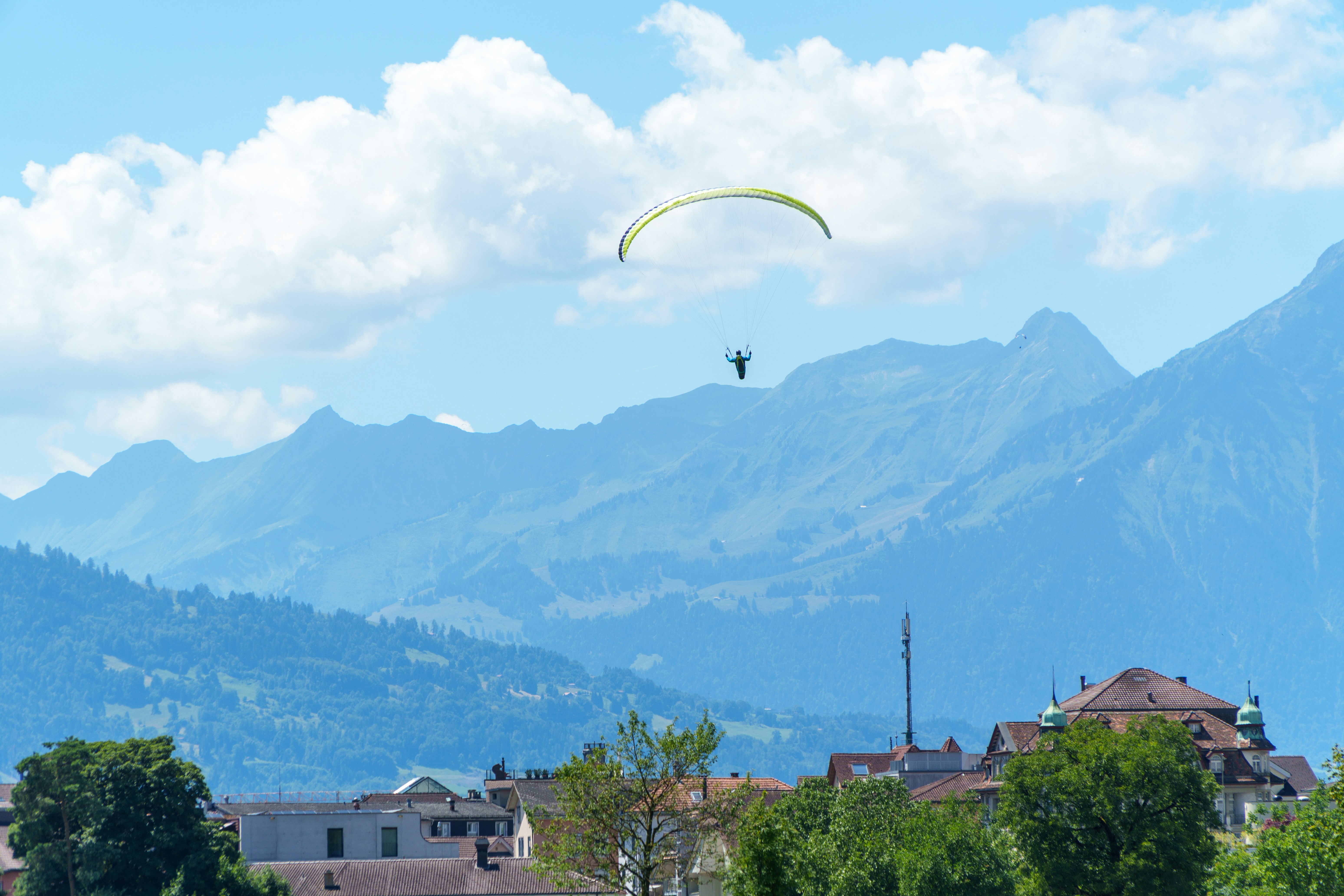 Glide Above the Alps: Paraglider Over a Mountain Town
