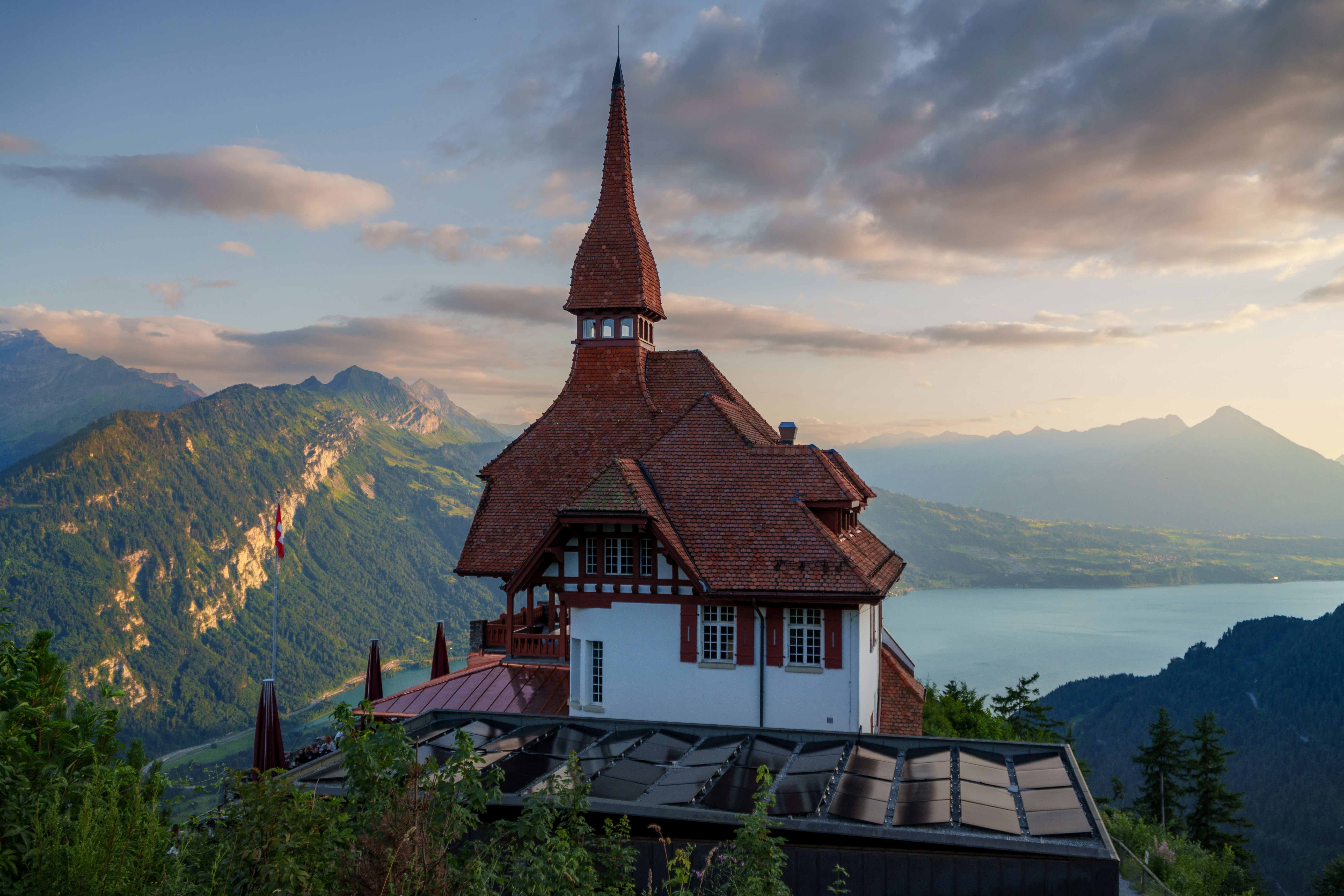 Red-Spired Alpine Chalet Framed by Lake and Ridge at Golden Hour