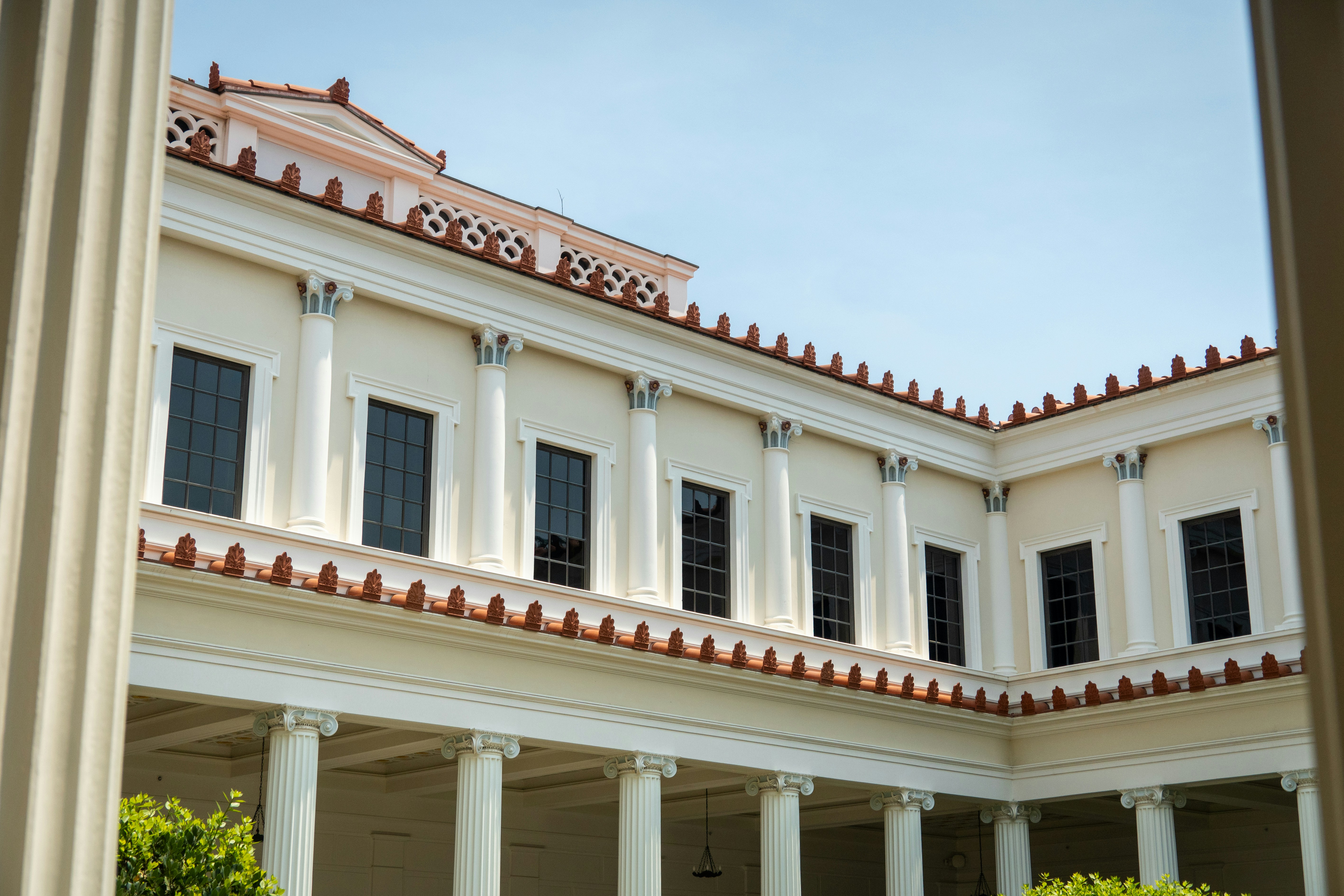 Elegant colonial architecture featuring tall windows and decorative rooflines framed by lush greenery.