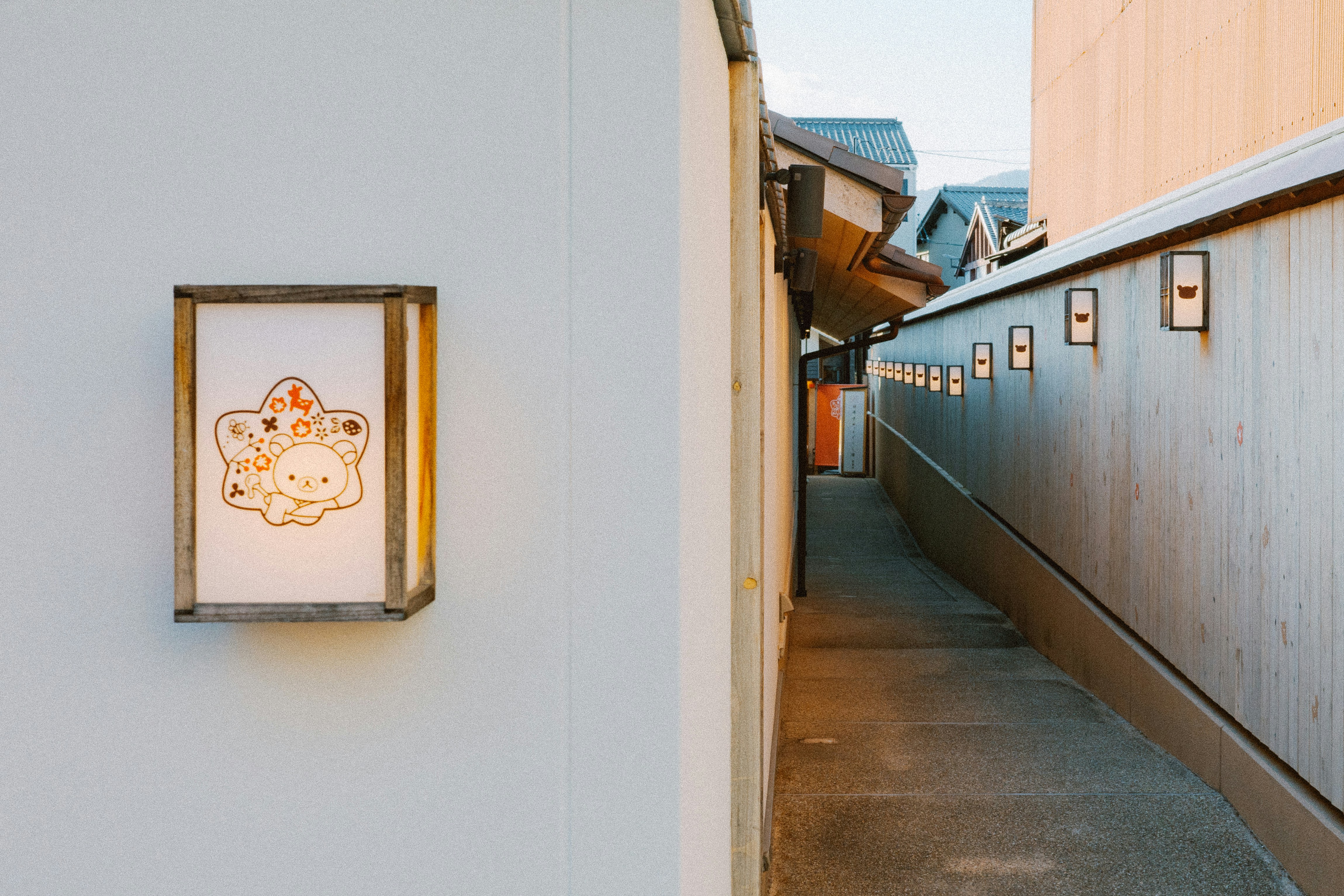 Narrow alleyway with a lit artwork on the wall.