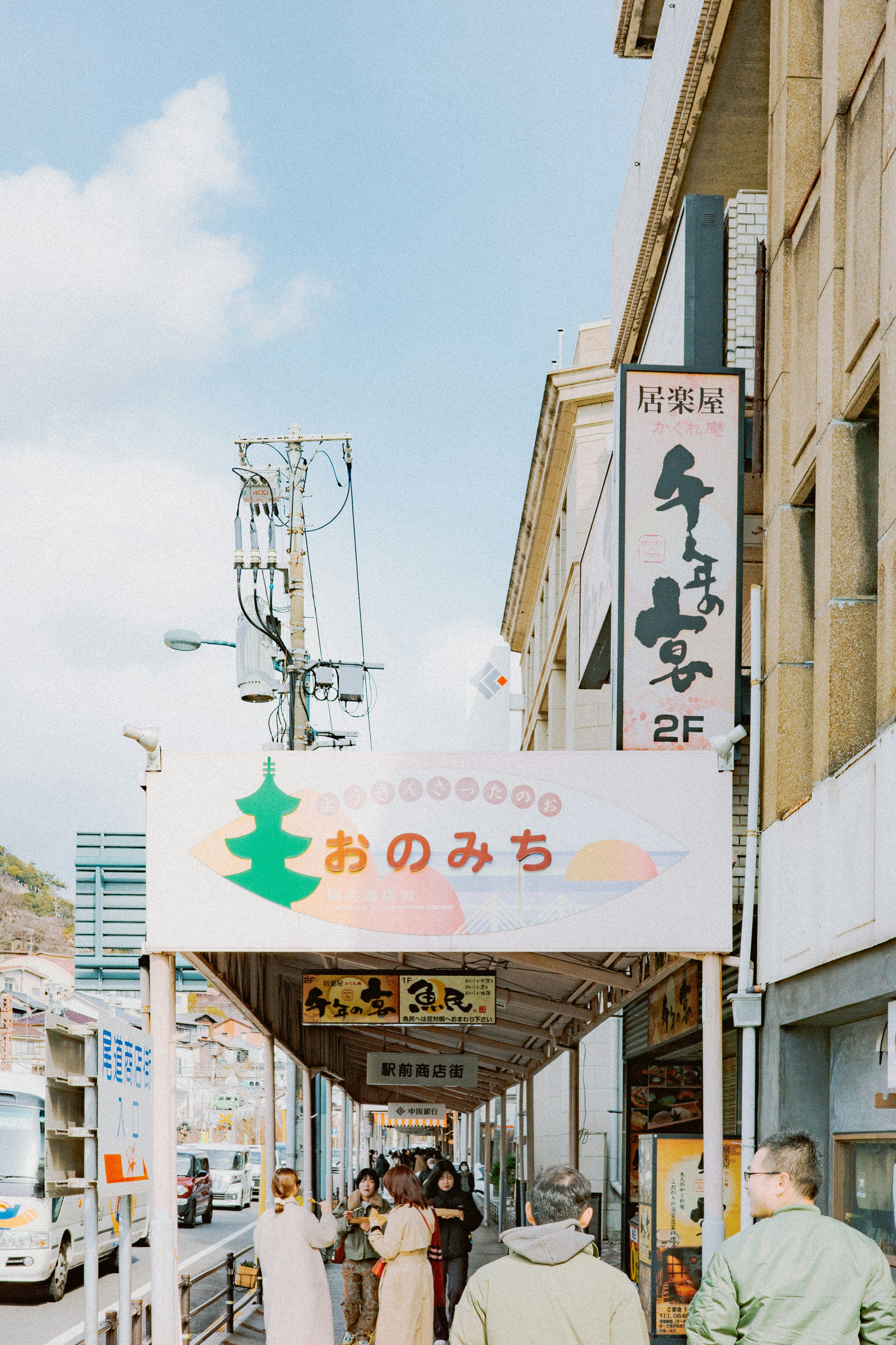 Vibrant street scene showcasing a bustling marketplace with pedestrians and colorful signage in a quaint town.