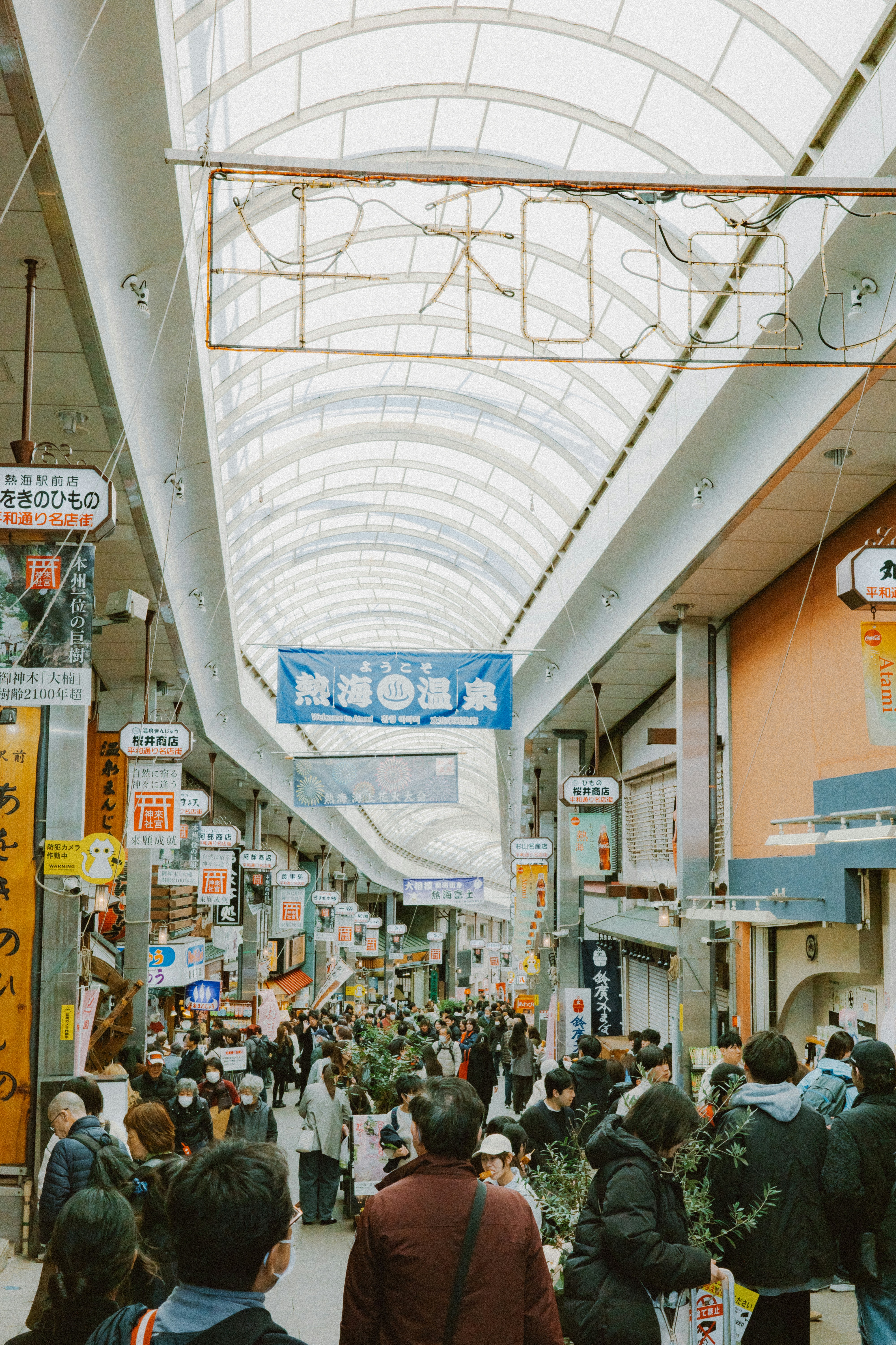 People are shopping in a crowded, covered market.