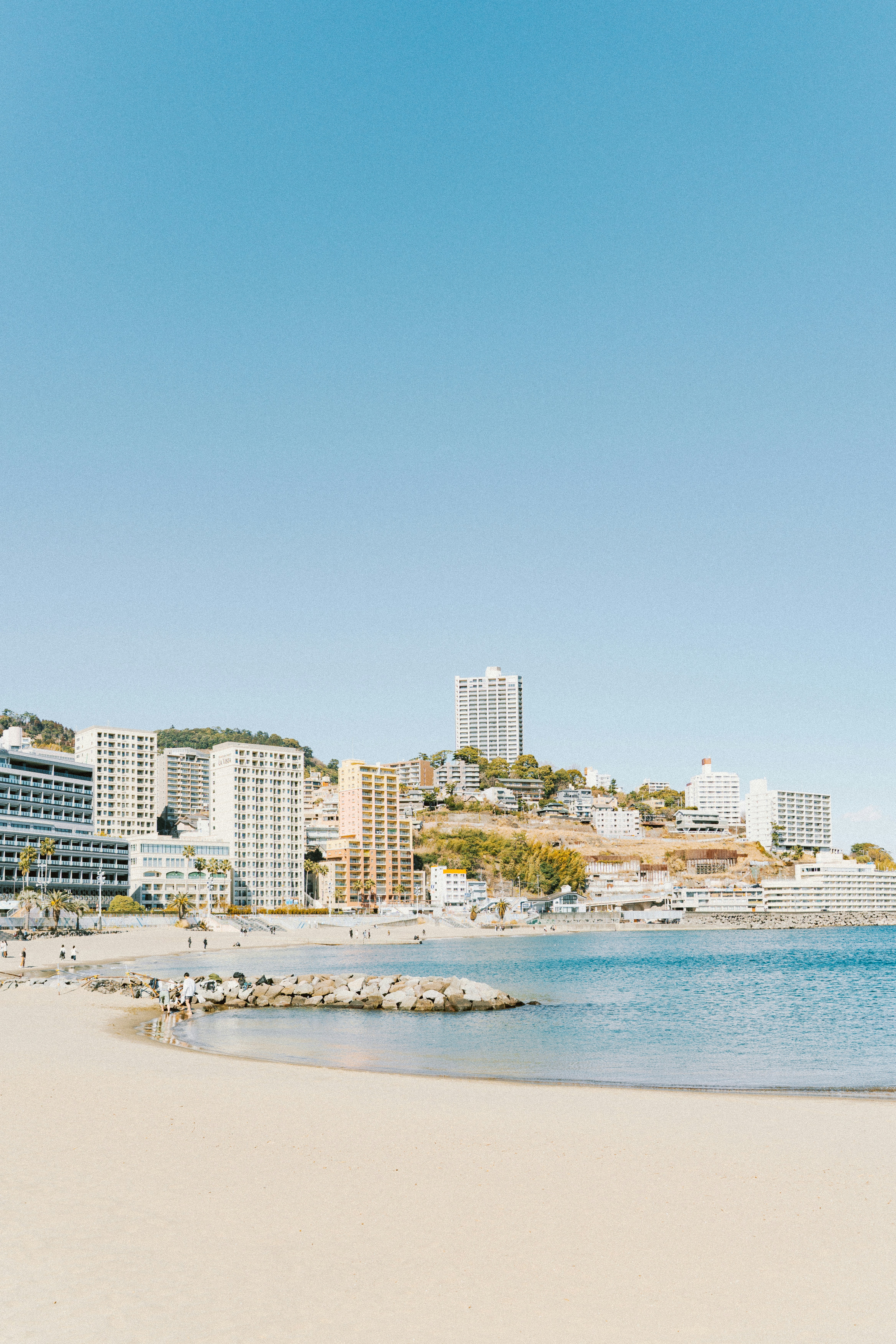 Beach scene with buildings under a blue sky.
