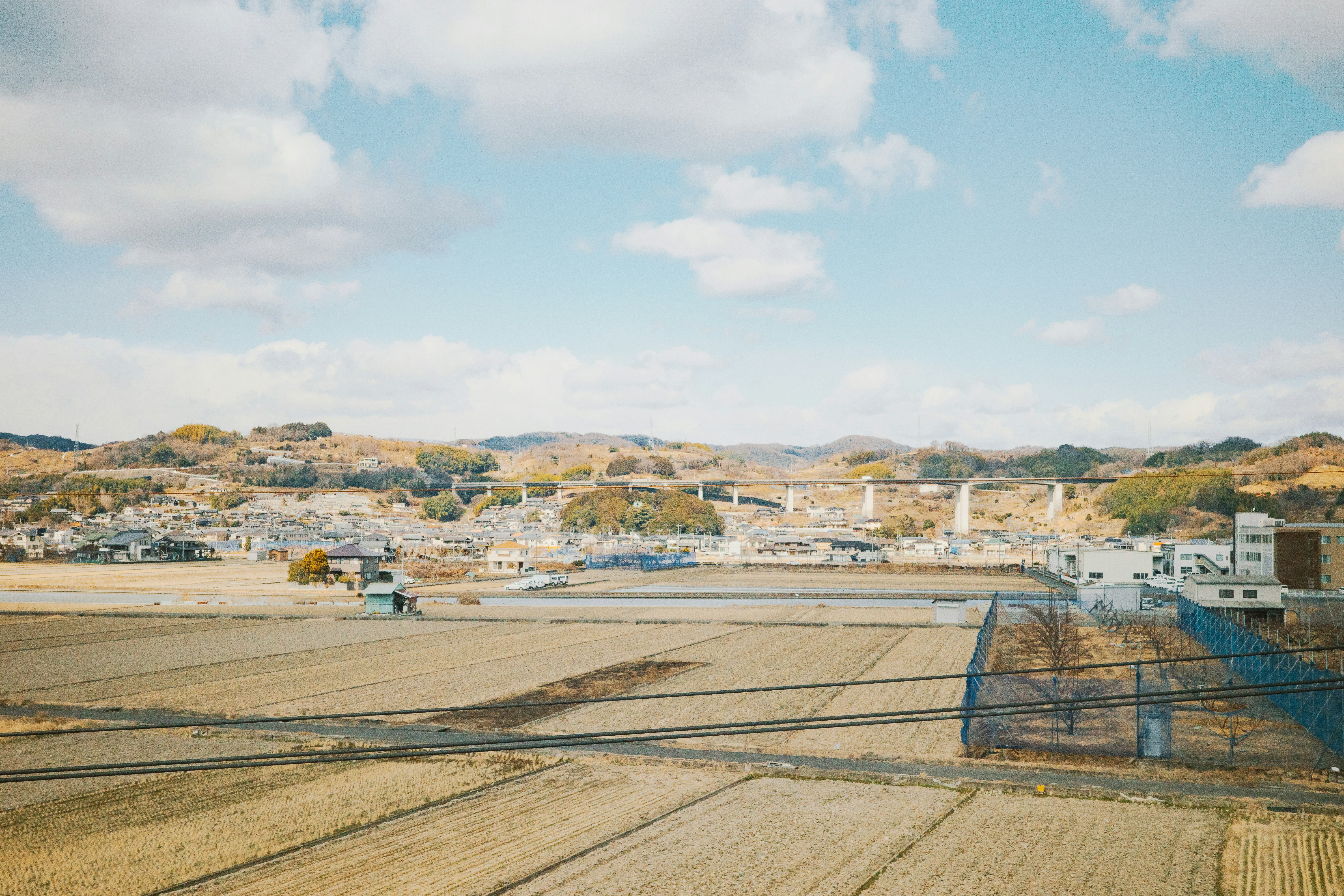 A rural landscape with fields and a blue sky.