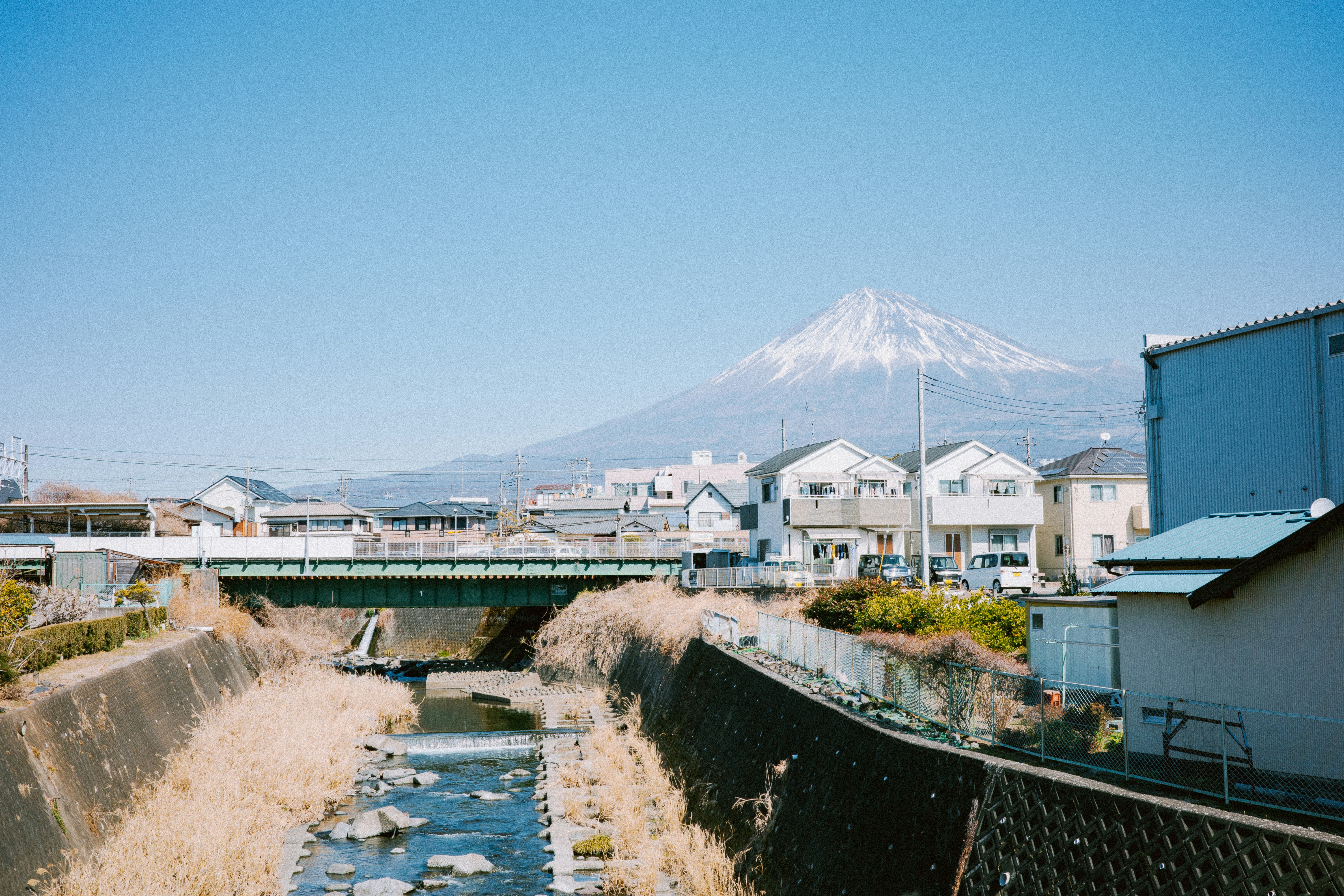 Fuji Over the Riverside: Snowcapped Summit Behind a Quiet Town