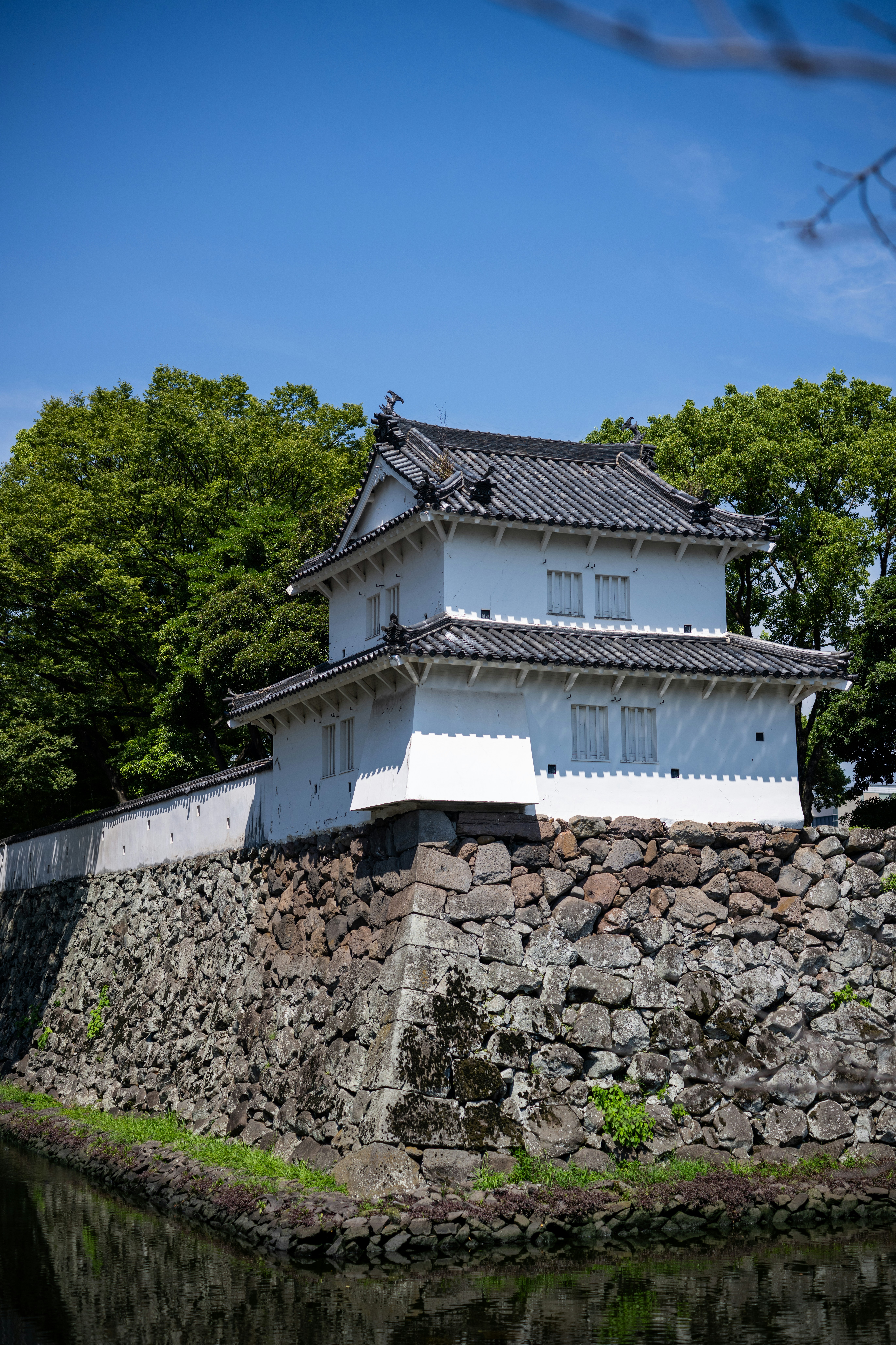 A japanese castle sits beside water.