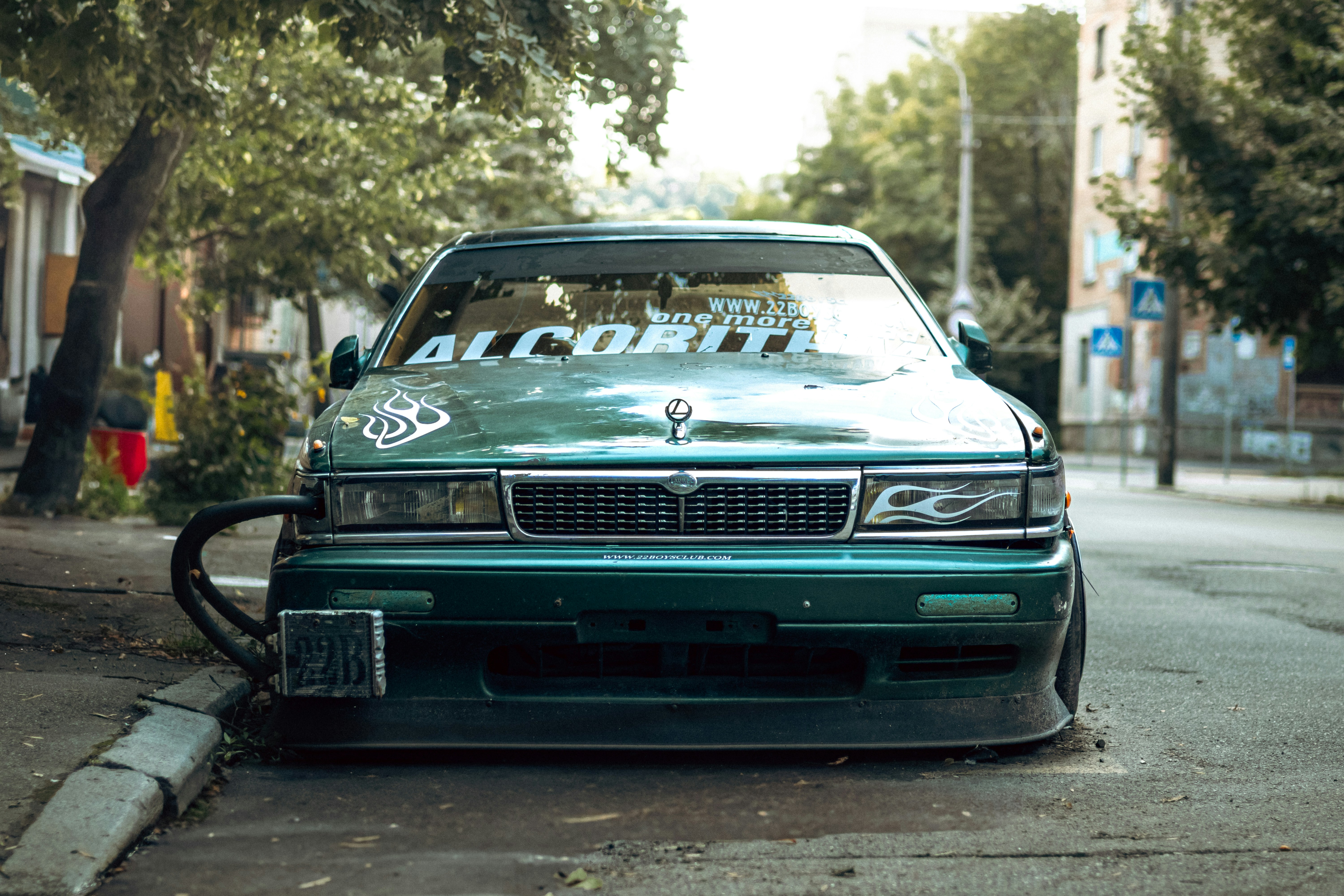 Here is a short caption for the image: a green car parks on the sidewalk.