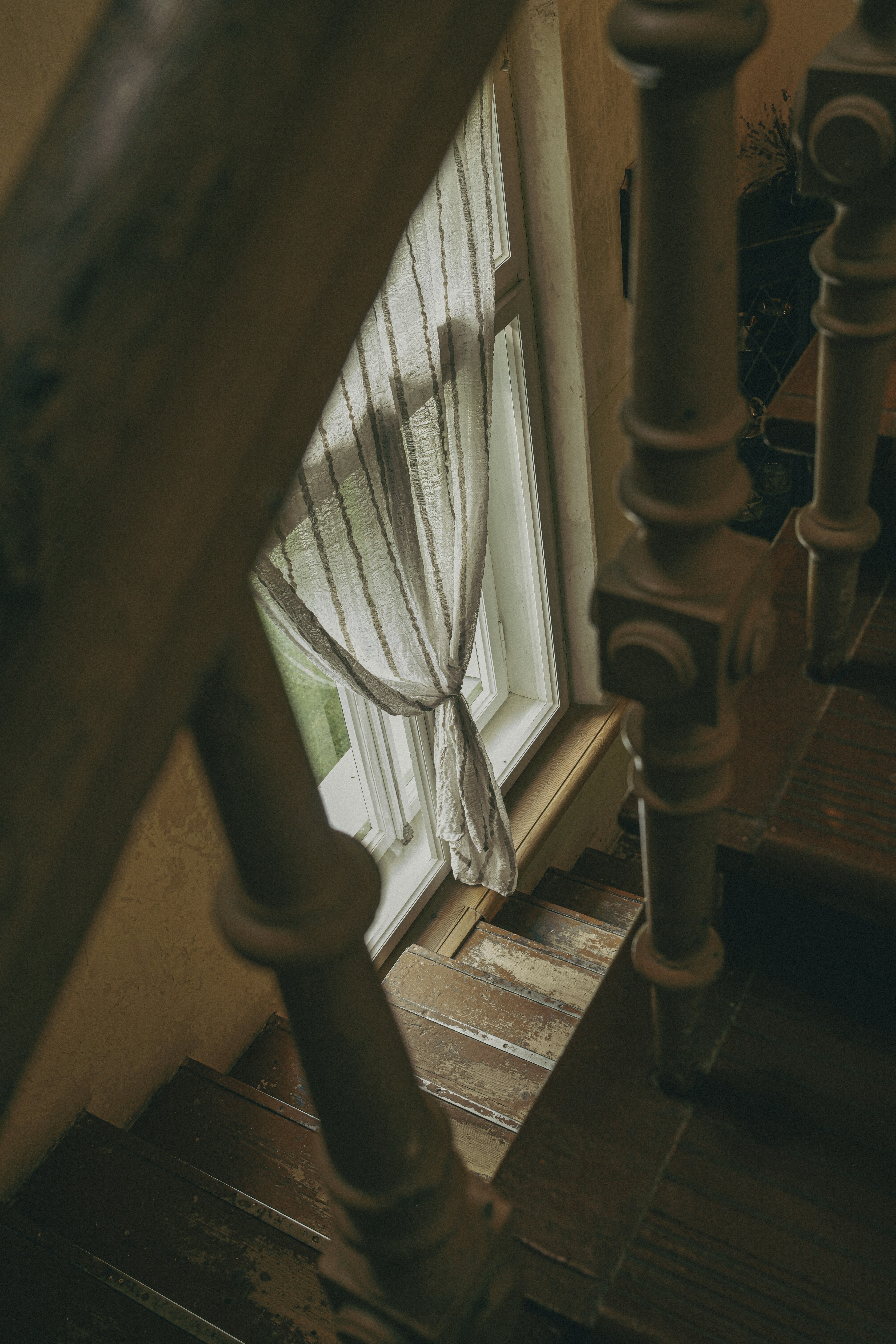 Staircase and window with a sheer curtain.
