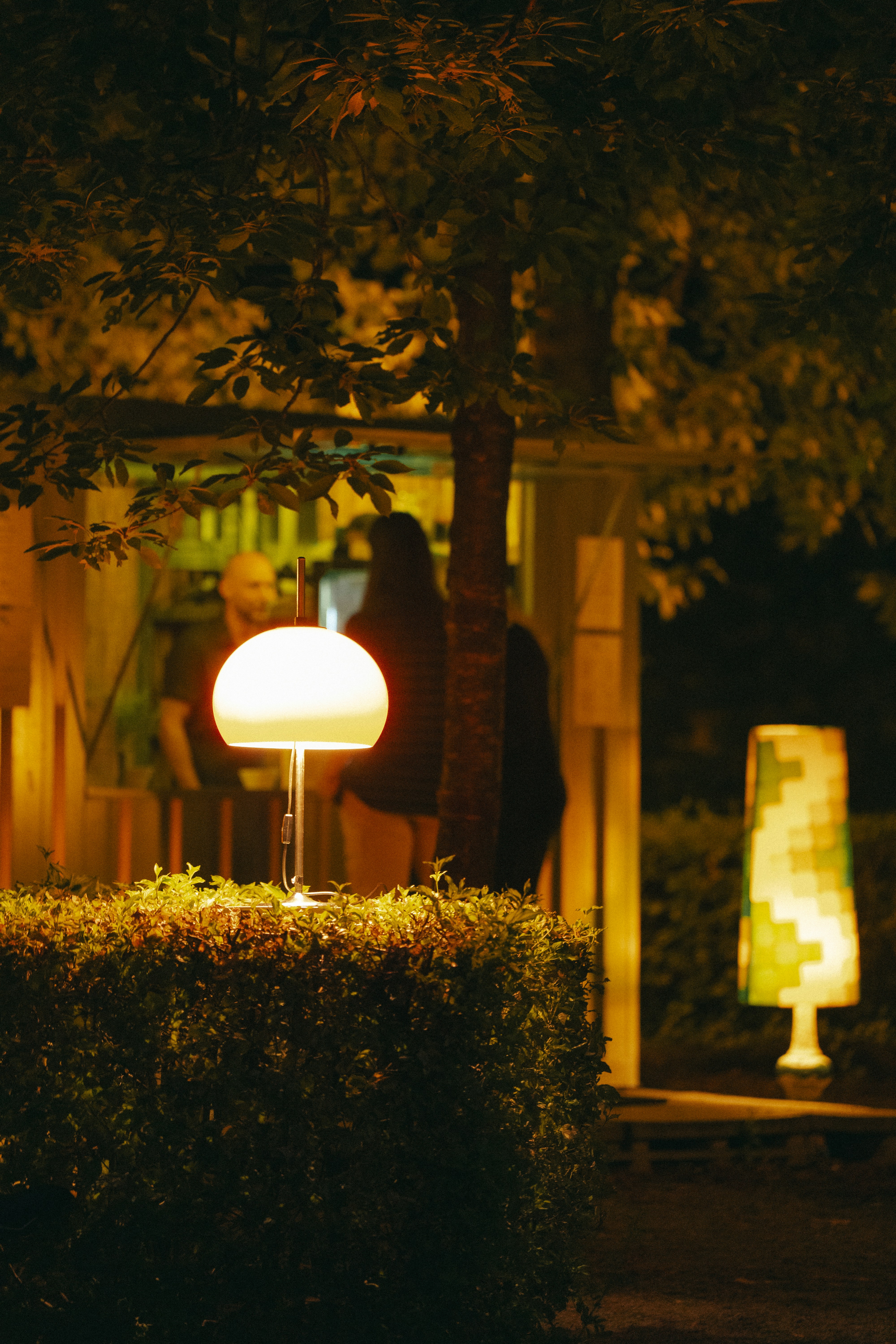 Lamps illuminate a nighttime outdoor scene.
