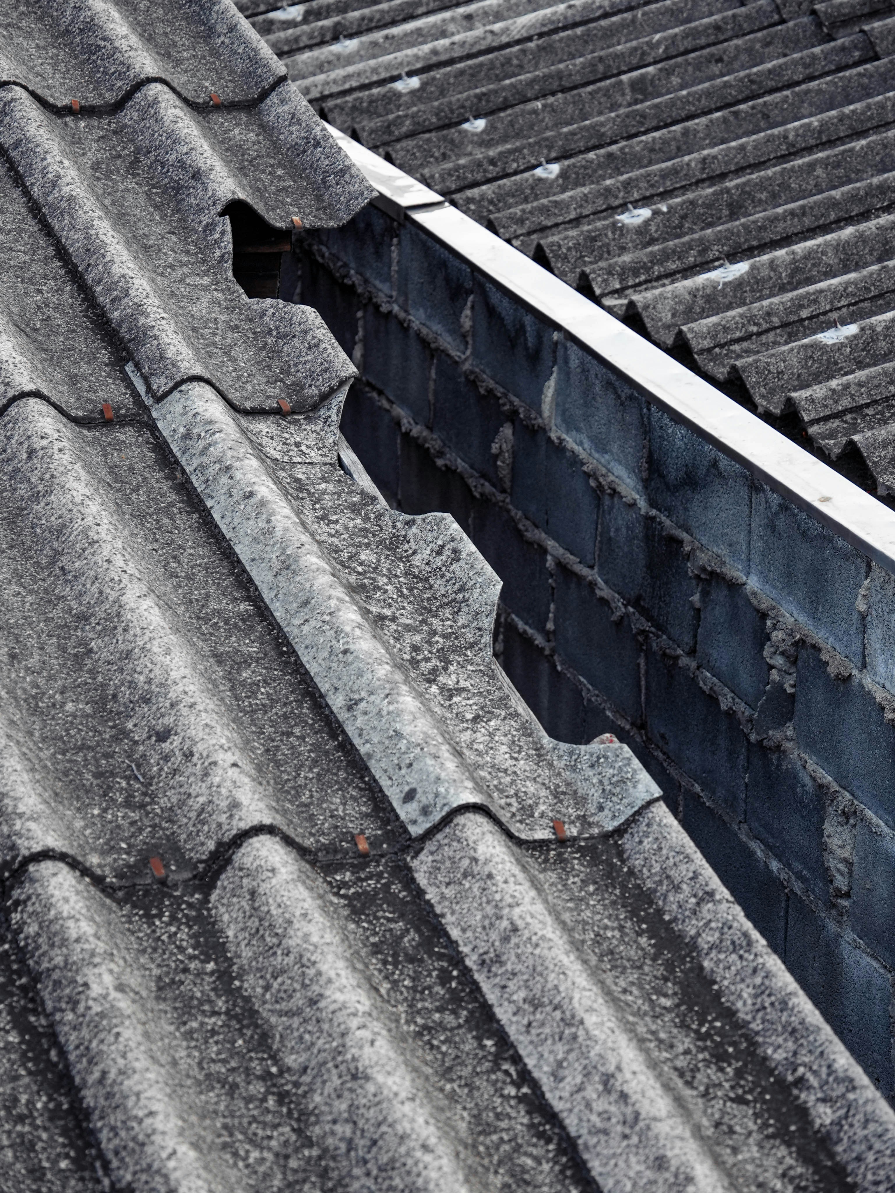 Layers of grey slate on roofs | Damaged roof with gutter and tiles.