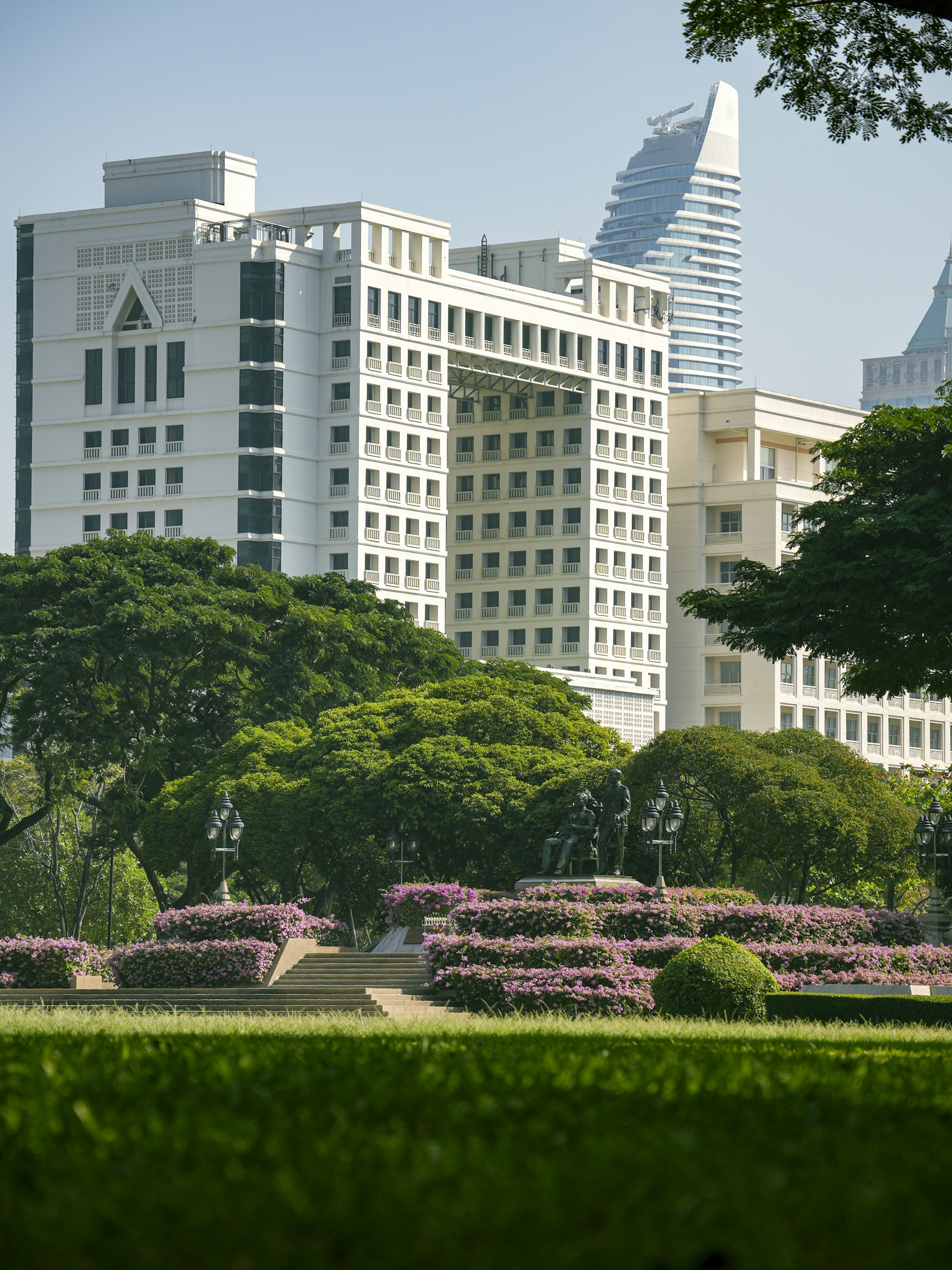 Buildings rise above a park with colorful flower beds.